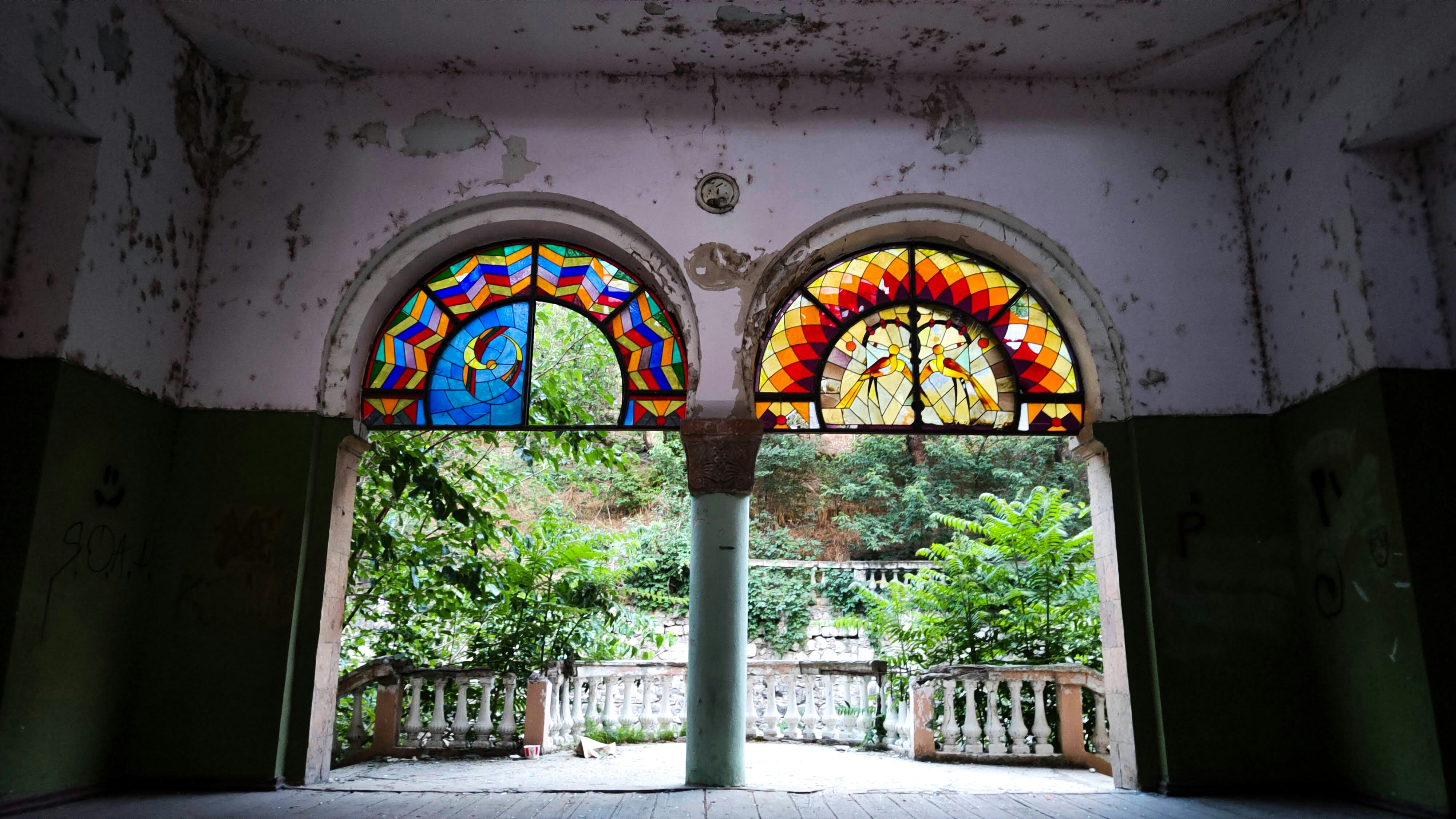 Sunlit Arcades: Stained Glass Windows Framing a Lush Courtyard