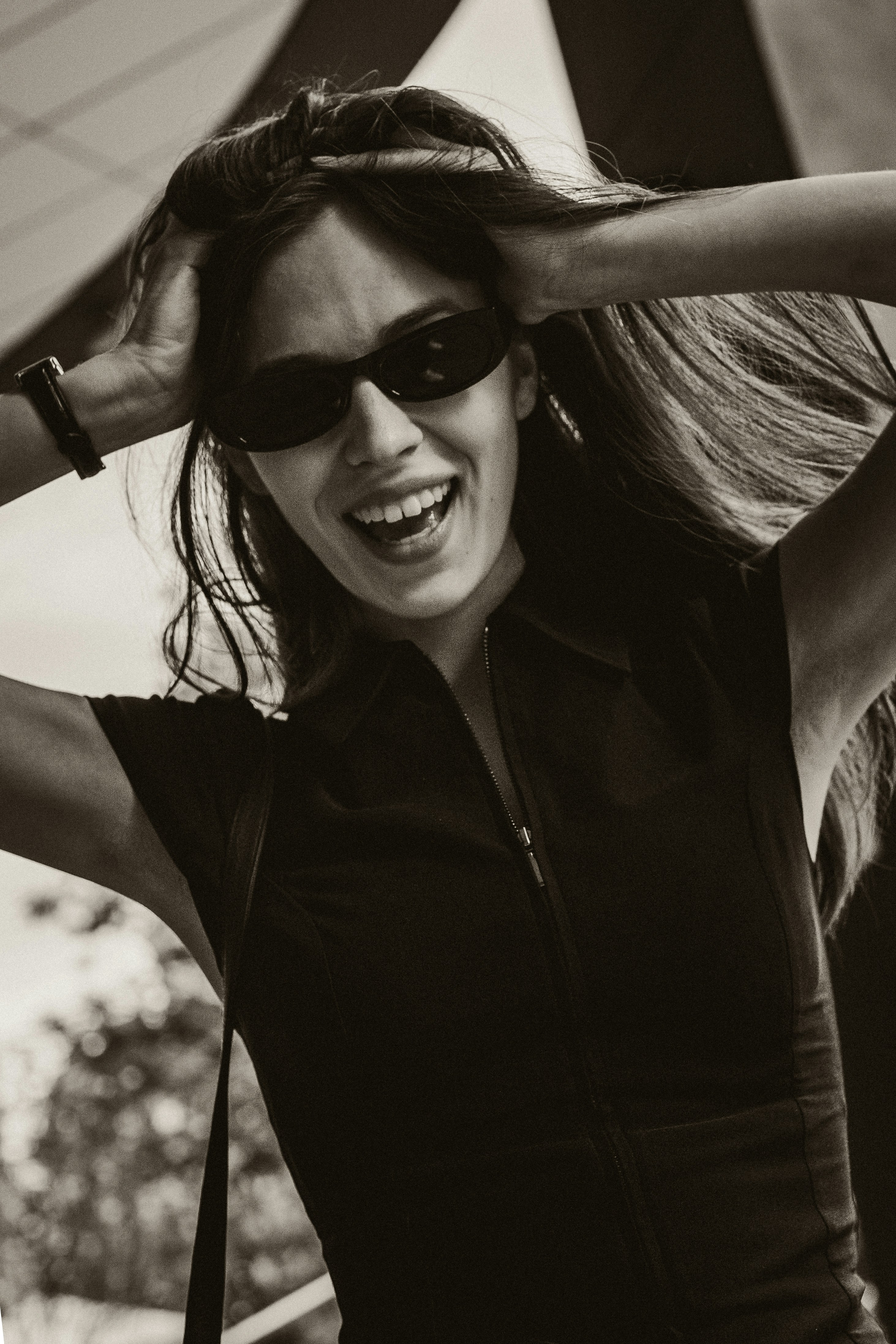 Energetic grin in motion: sunglasses and wind-sculpted hair