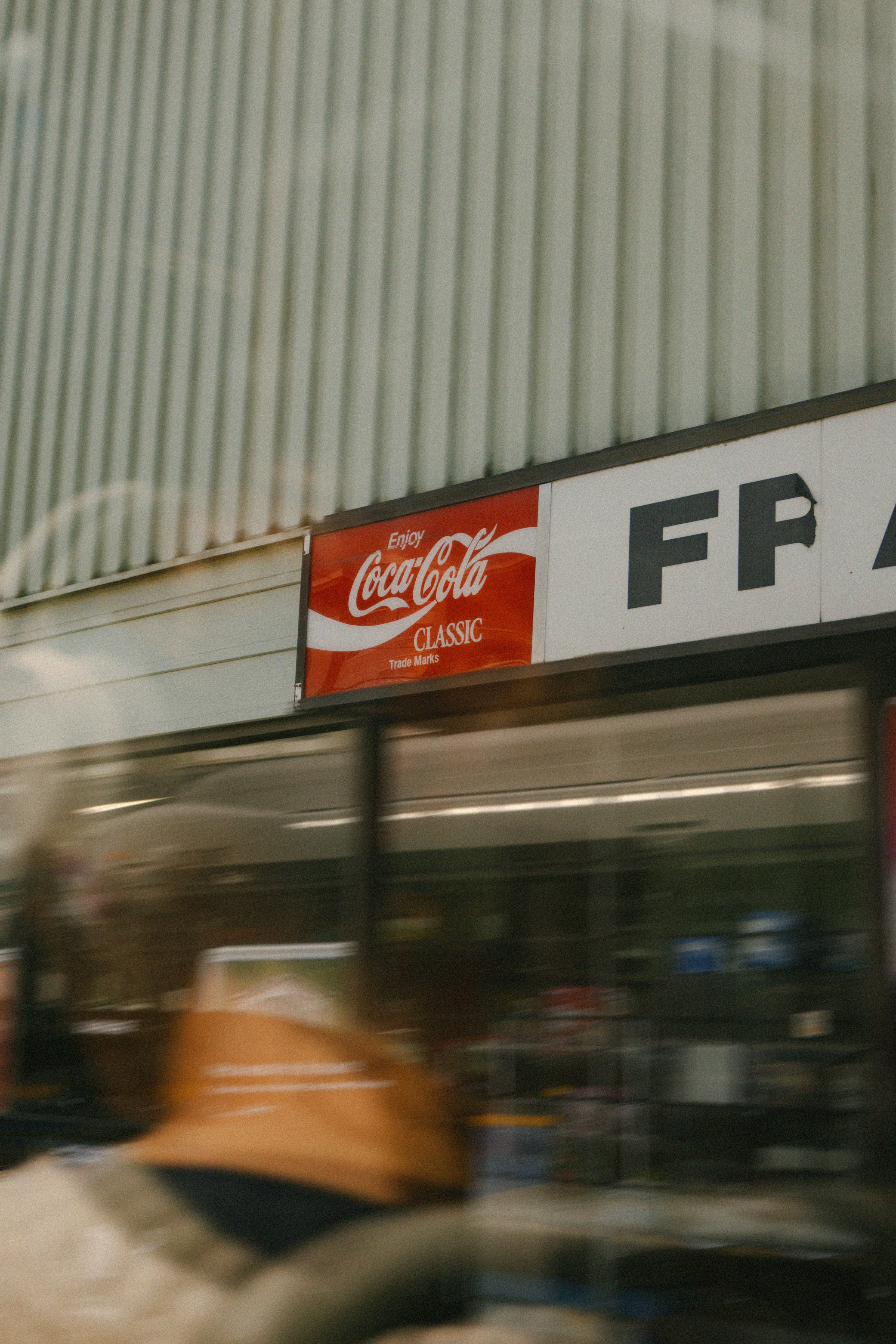 Coca-Cola Sign Framed by Industrial Facade Between Blurred Details