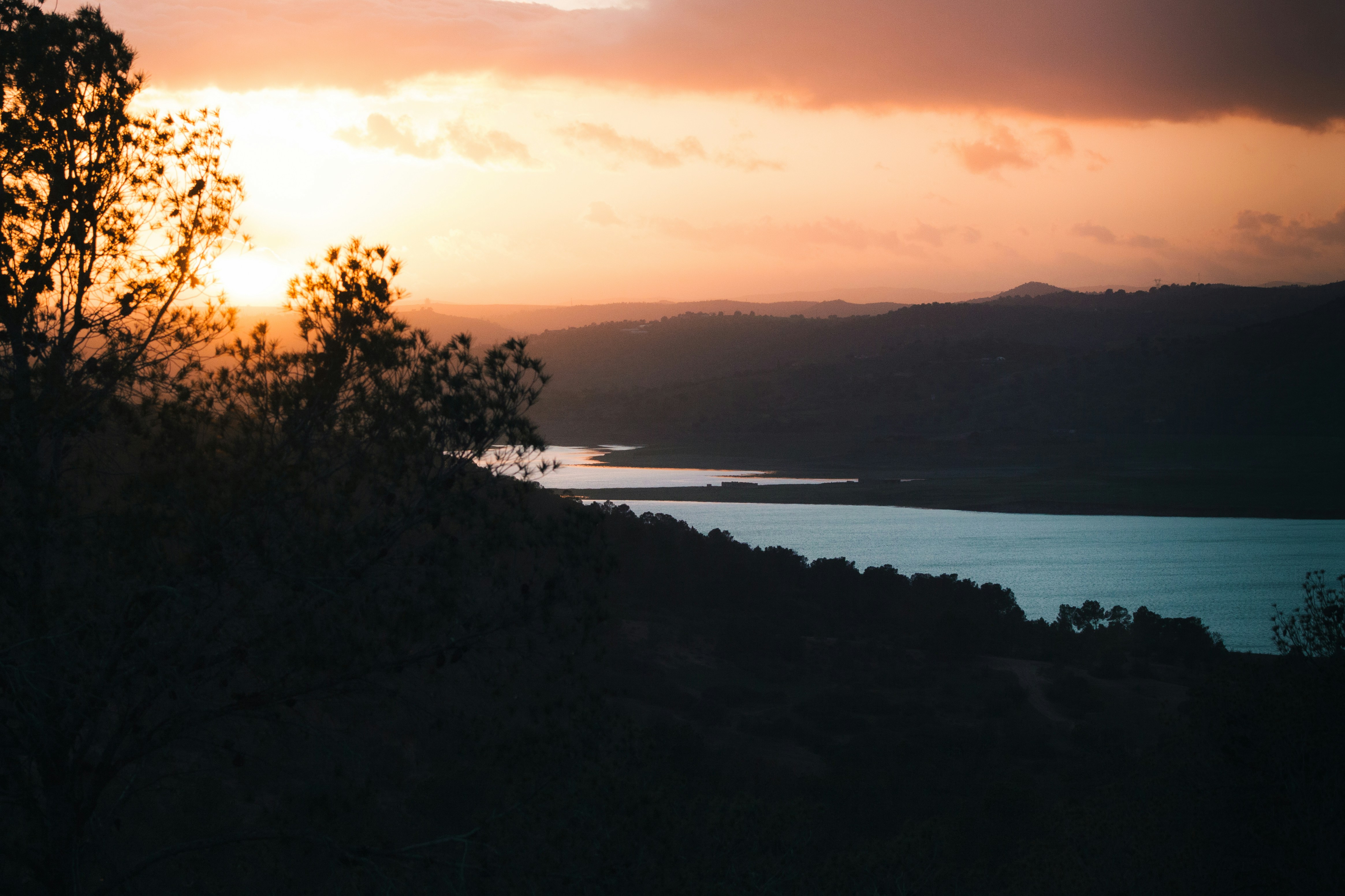 Sunset Over a Quiet Lake framed by silhouetted hillside