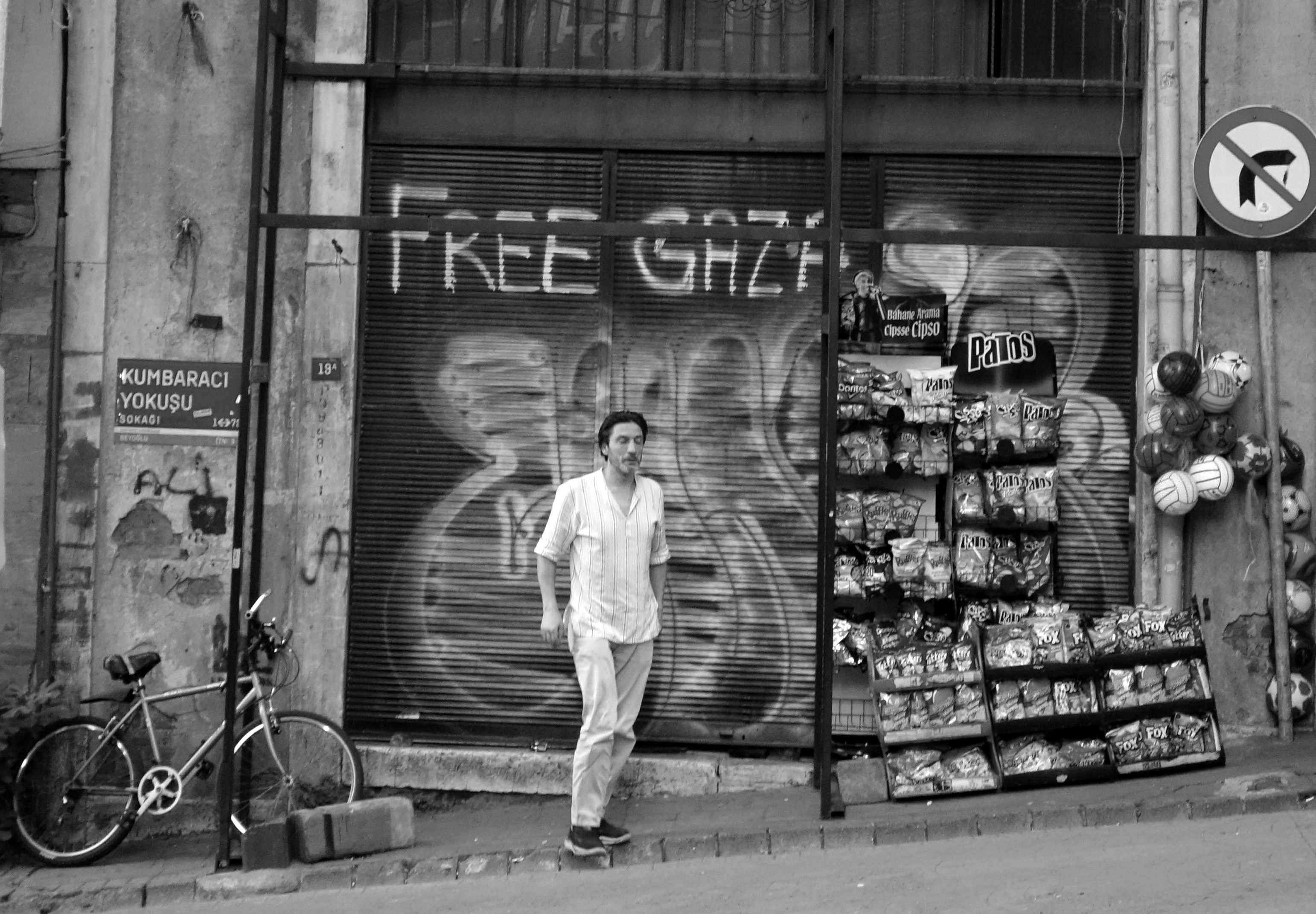 Man in front of shuttered storefront with graffiti and snack rack