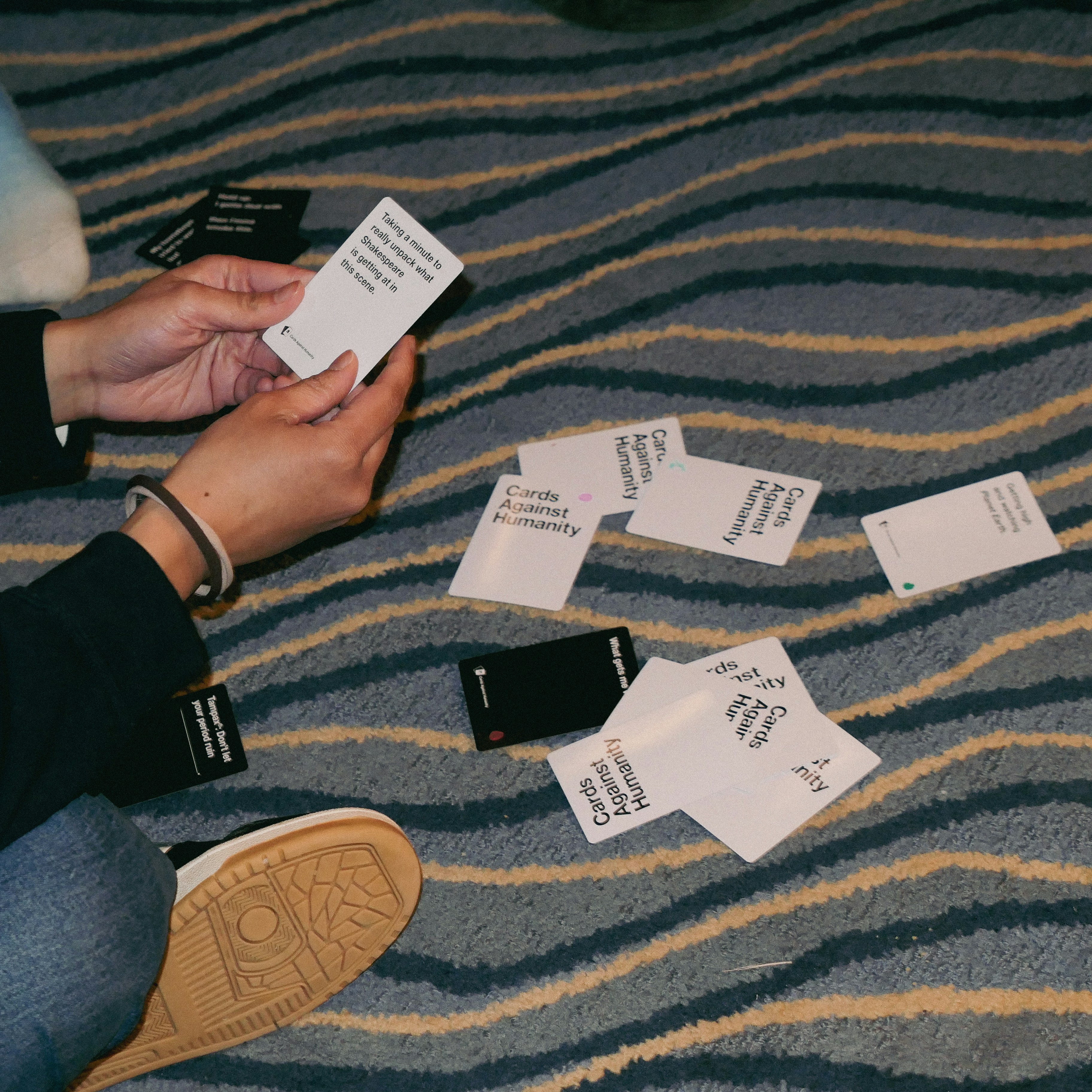 Hands Spread Across Playing Cards on a Striped Rug