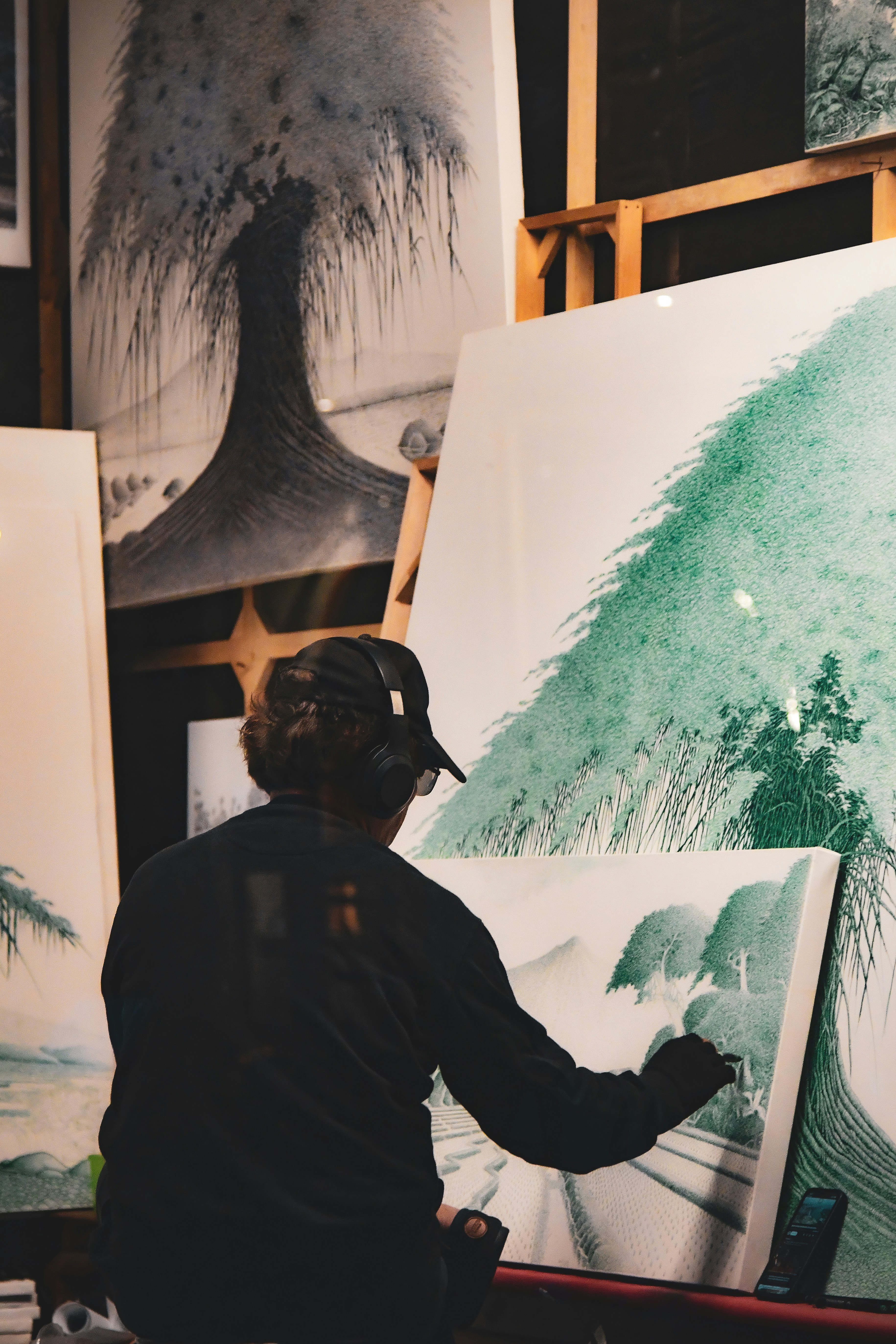 Brushstroke Studio: Artist in Focus Amid Large Green Canvas