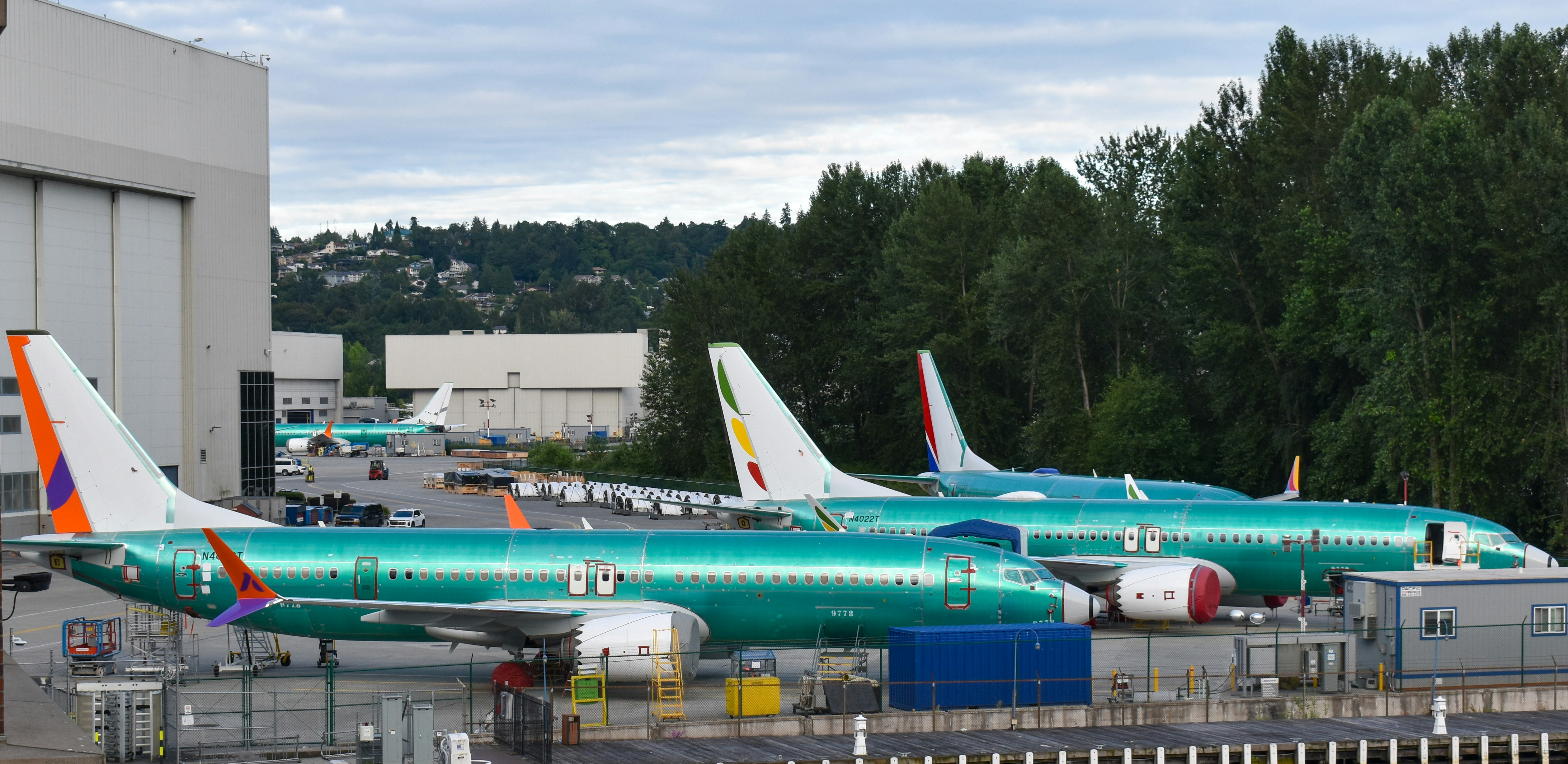  teal-hued jetshed: parked airliners line the tarmac under a cloudy sky