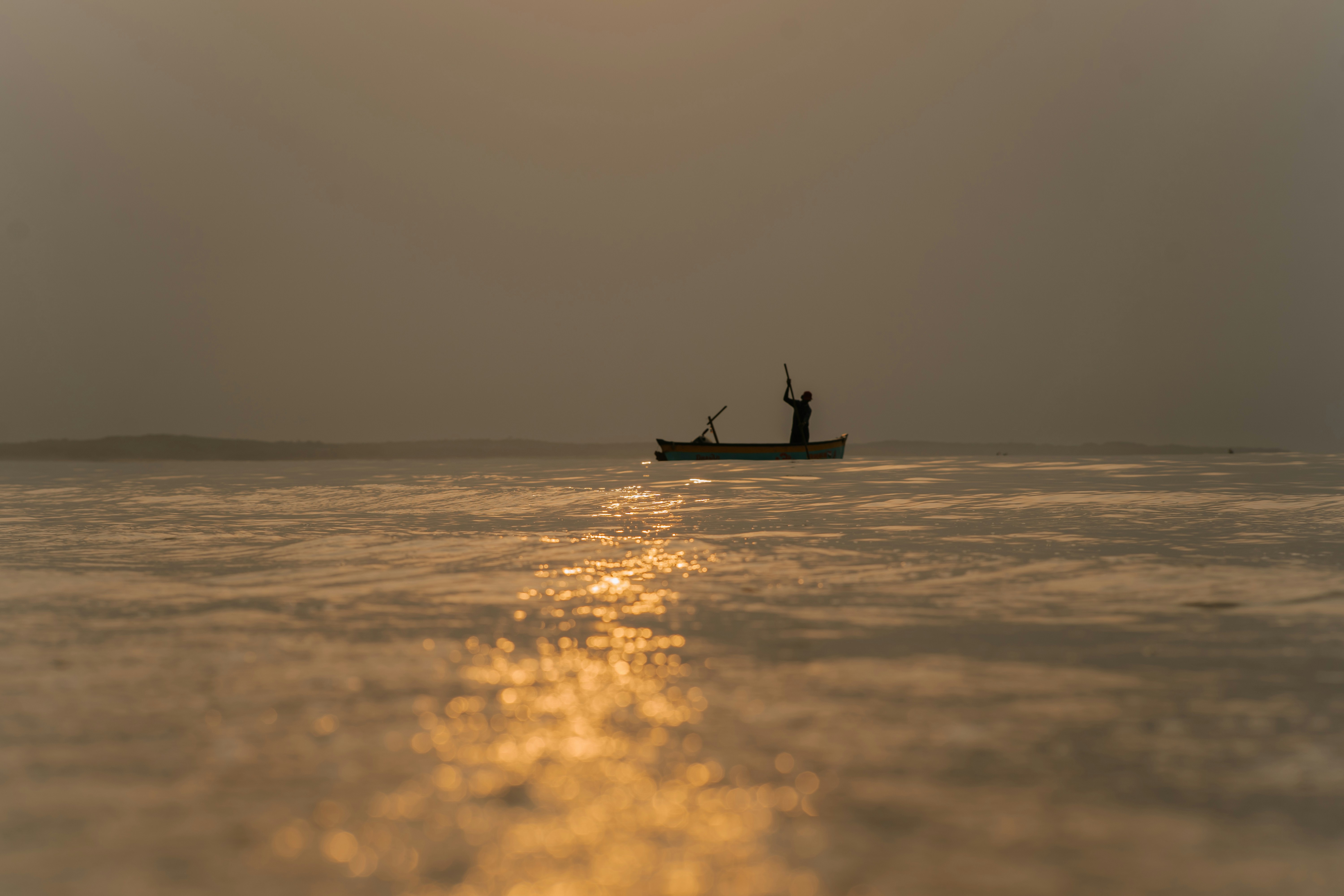 Silhouette at Sunset: Fisherman in a Distant Boat