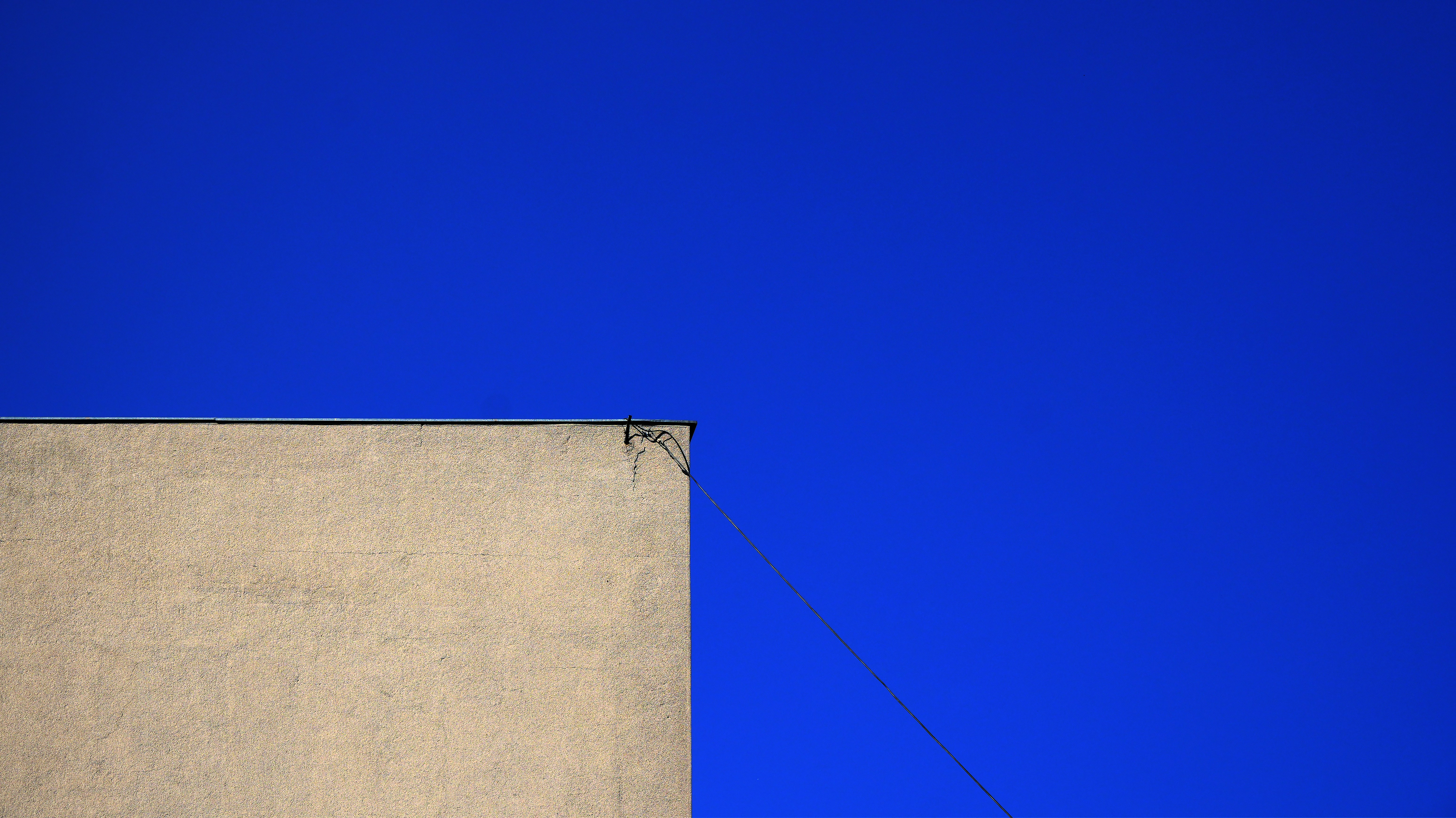 Corner of a Concrete Wall Reaching into a Pristine Blue Sky