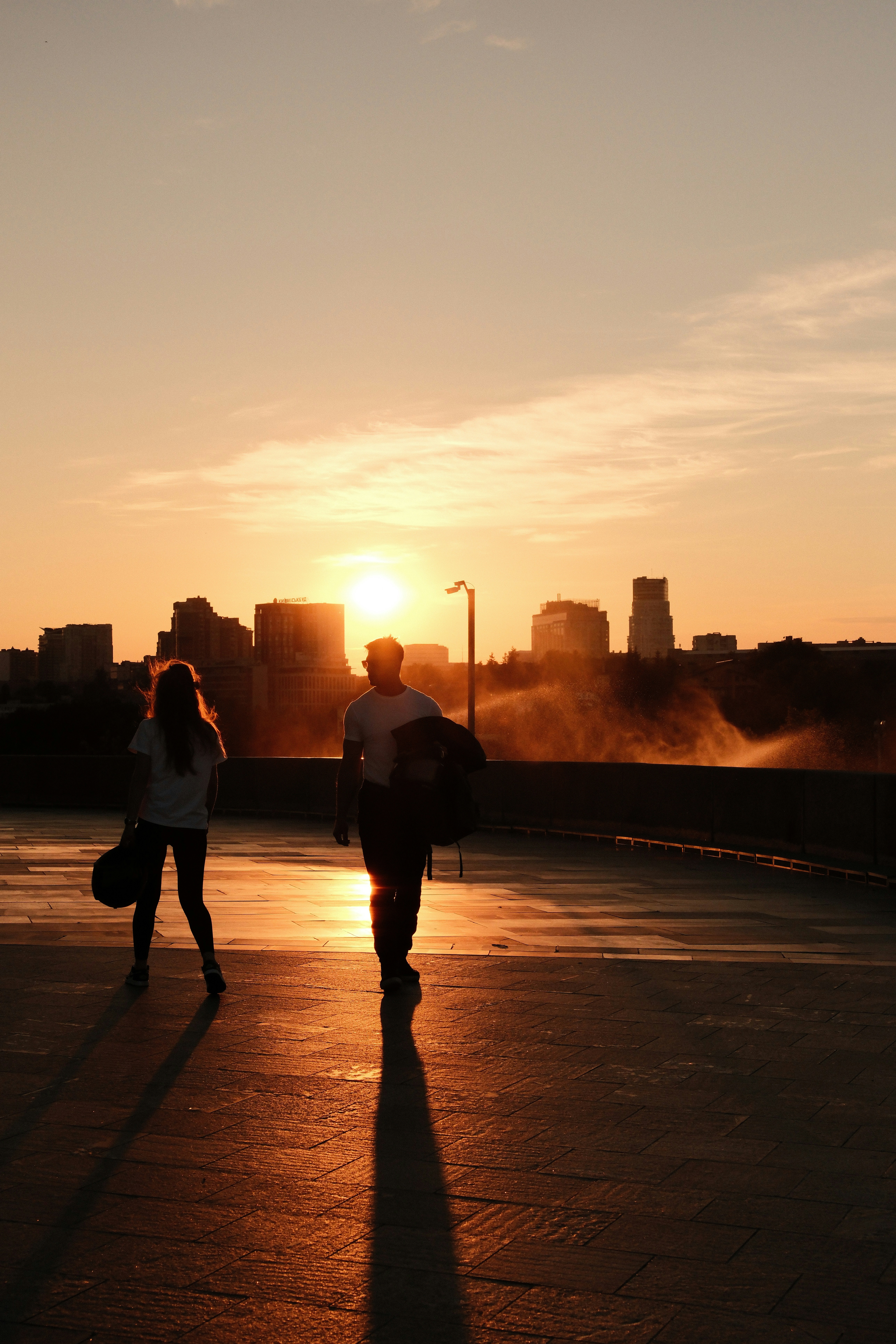 Silhouetted duo on a sunlit rooftop at dusk