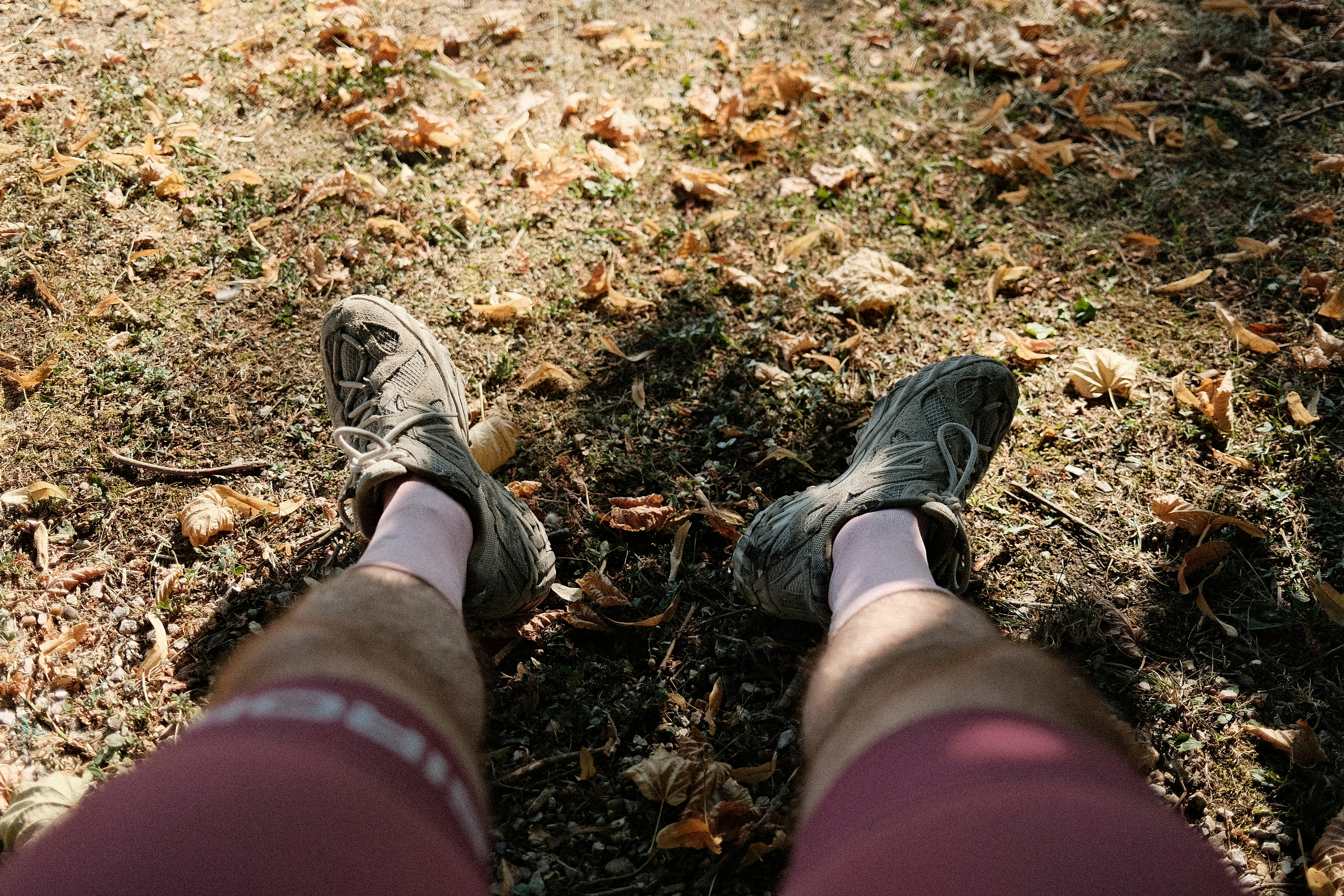 Grounded Pause: Feet in Sneakers Over Fallen Leaves
