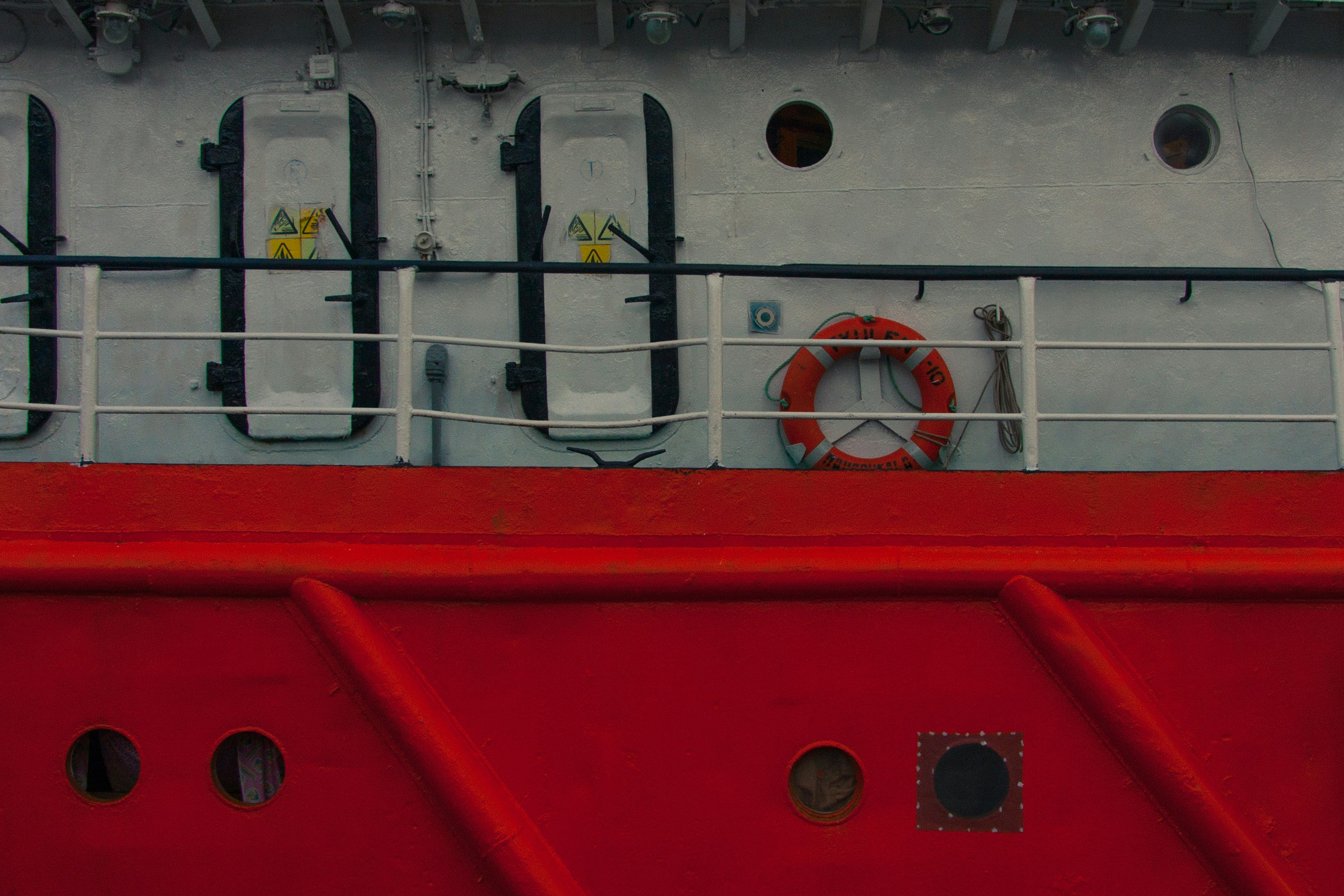 Red Hull, White Rail: A Close-Up of Maritime Structure and Lifebuoy