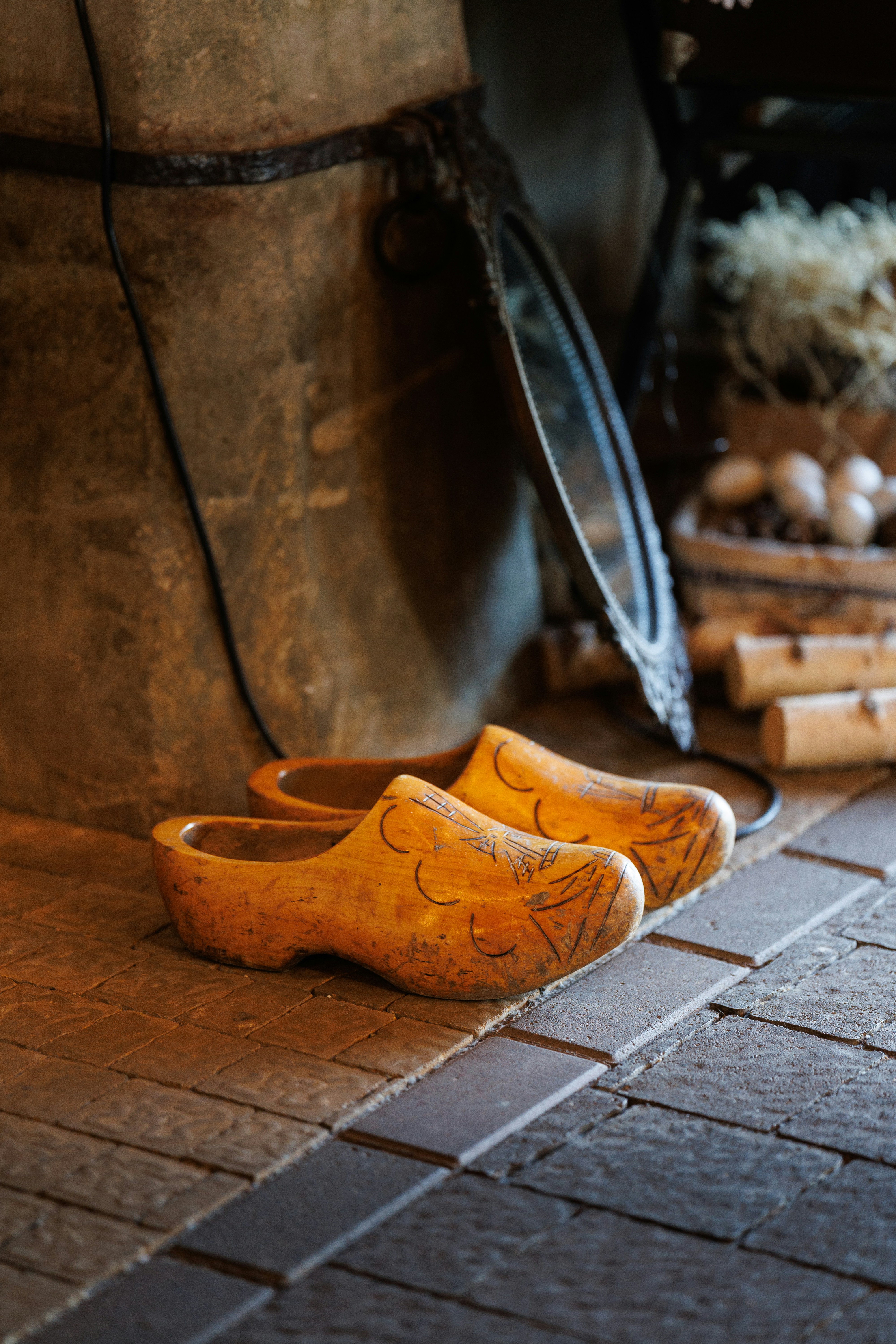 Wooden clogs rest by a rustic kitchen stove