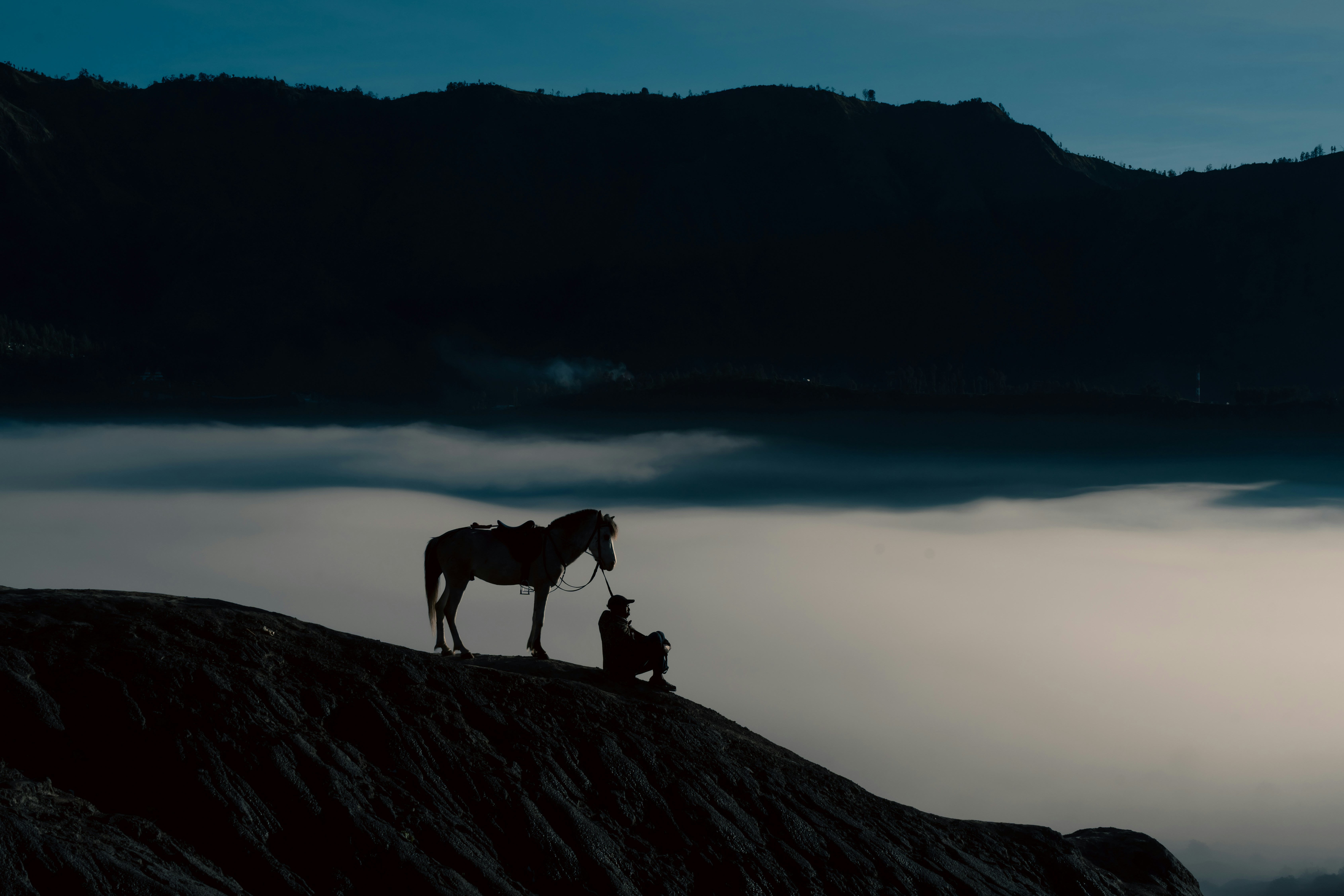 Silhouette on the Edge: A Horse and Figure at Dusk Over Mist
