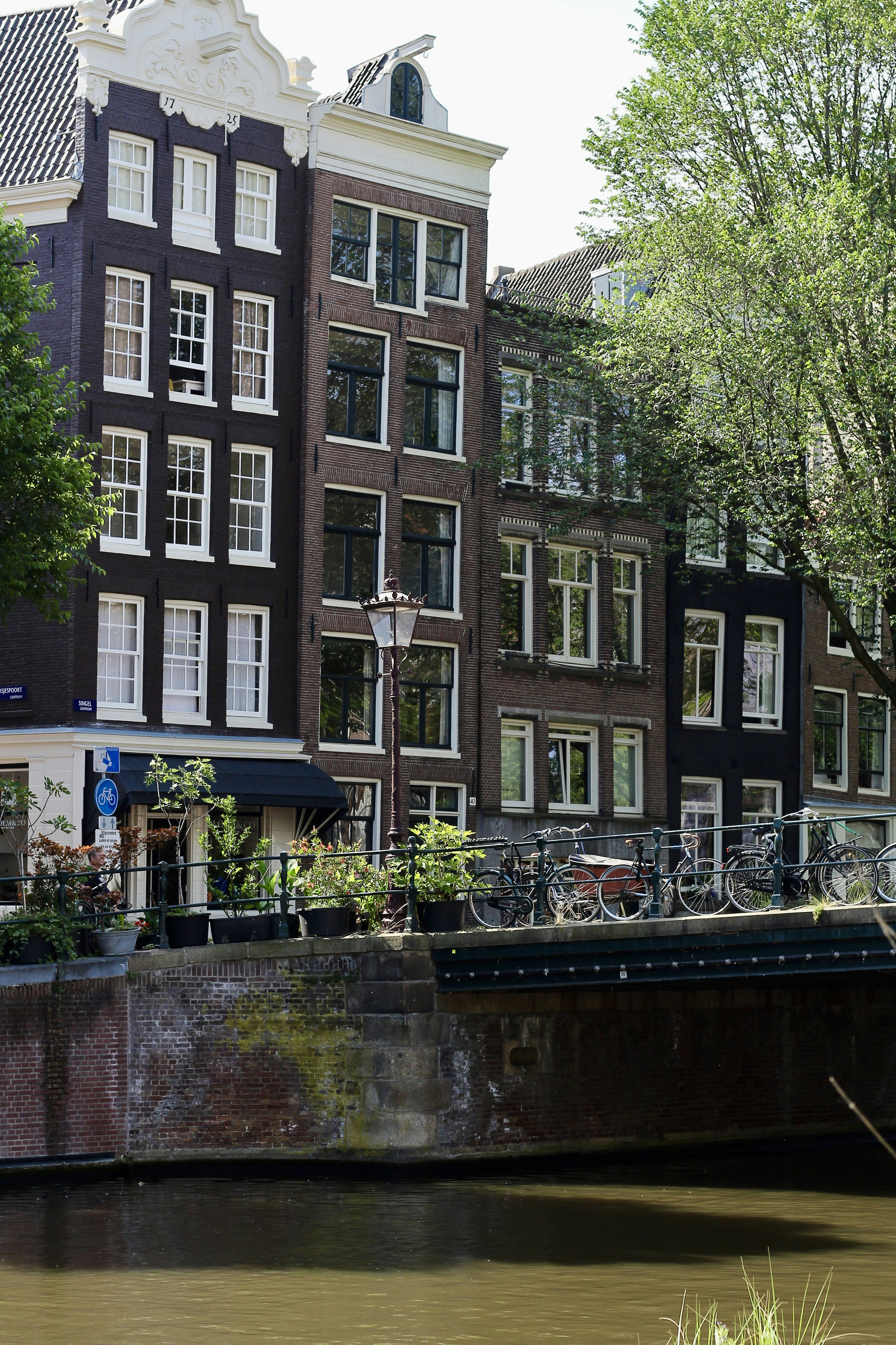 Sunlit facades along a canal: bicycles, bricks, and reflections
