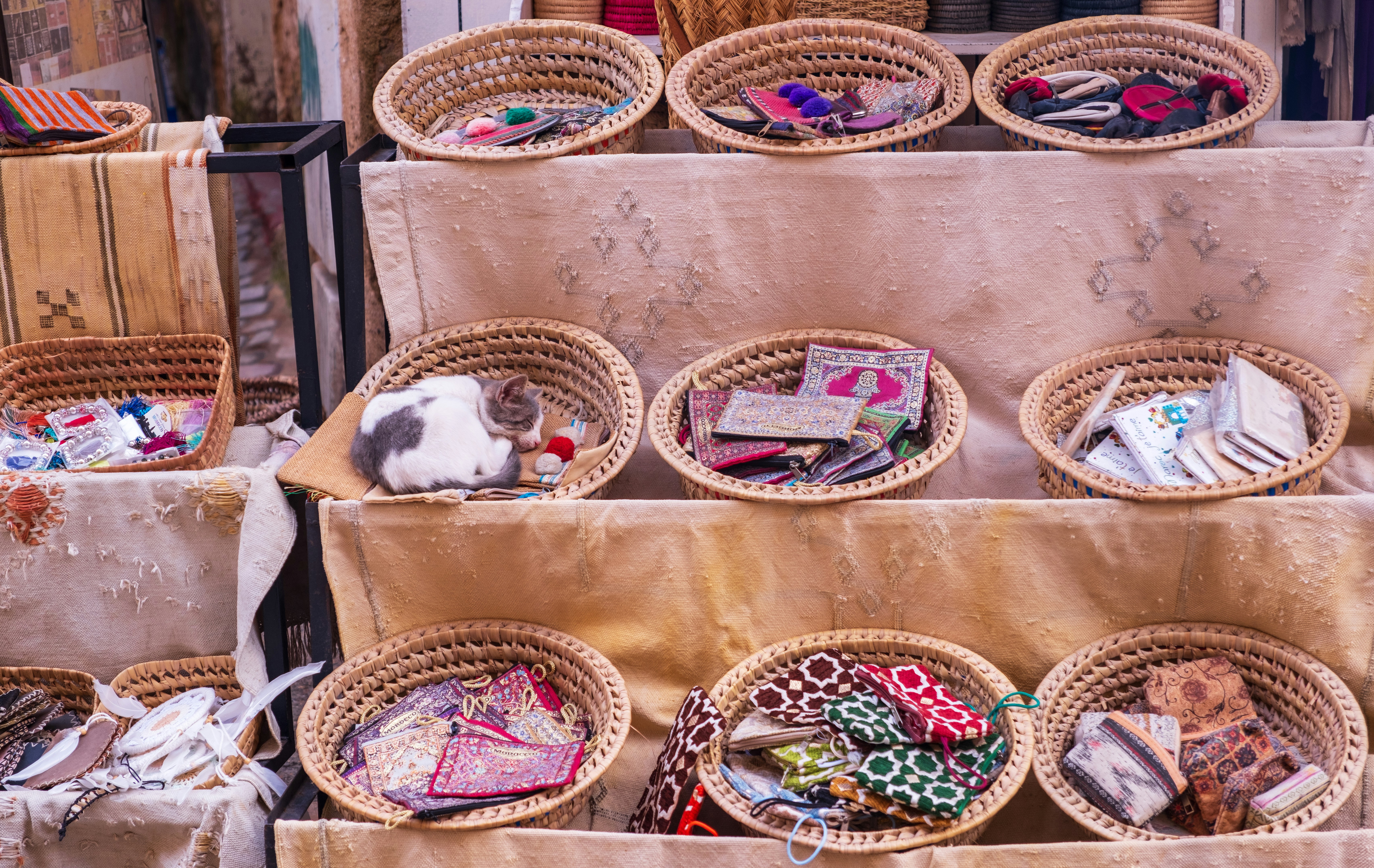 Colorful baskets filled with fabric scraps and small items line a shop display at a vibrant market stall.
