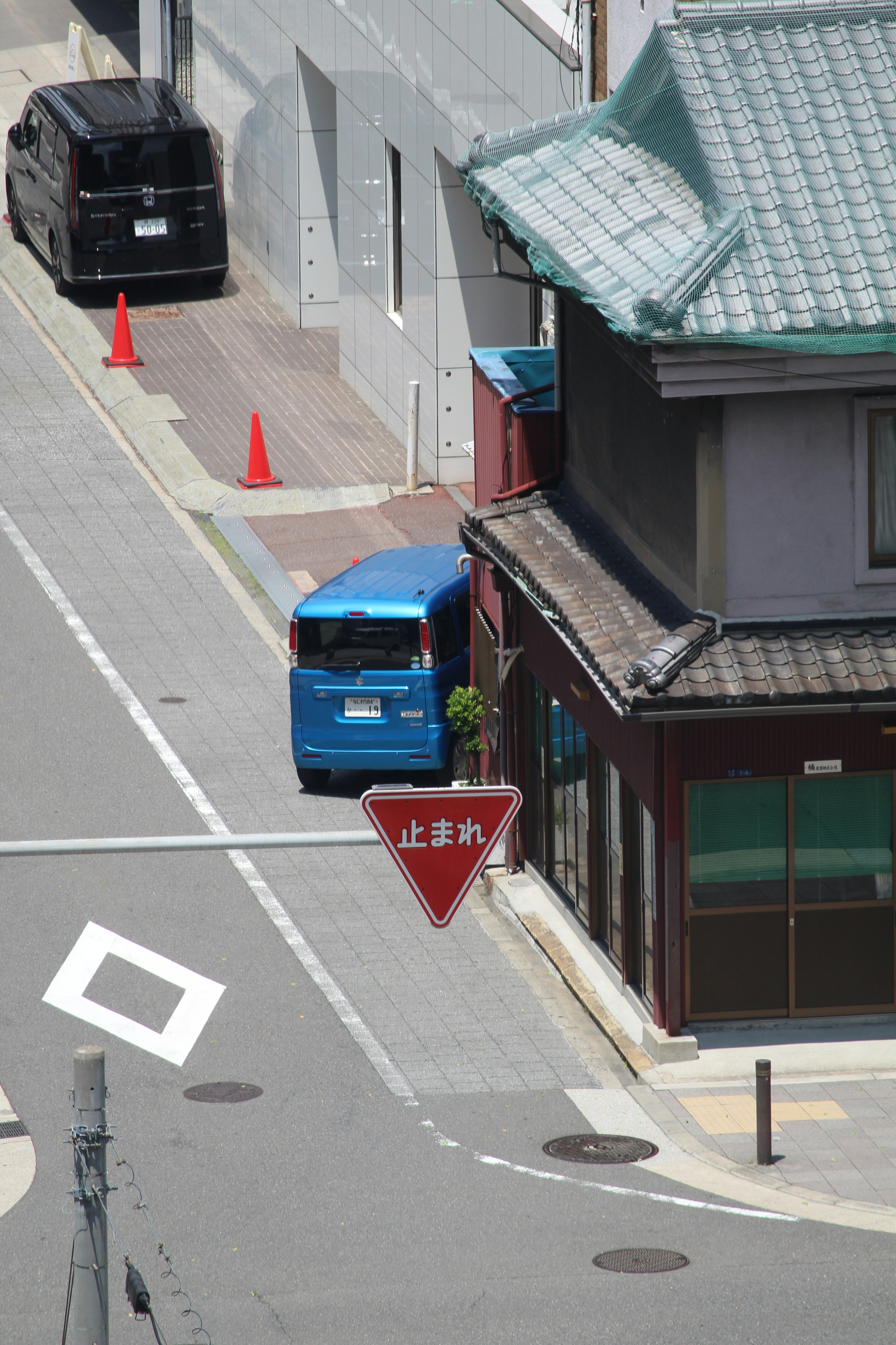Blue Van on a Quiet Street Corner Beside a Traditional Rooftop