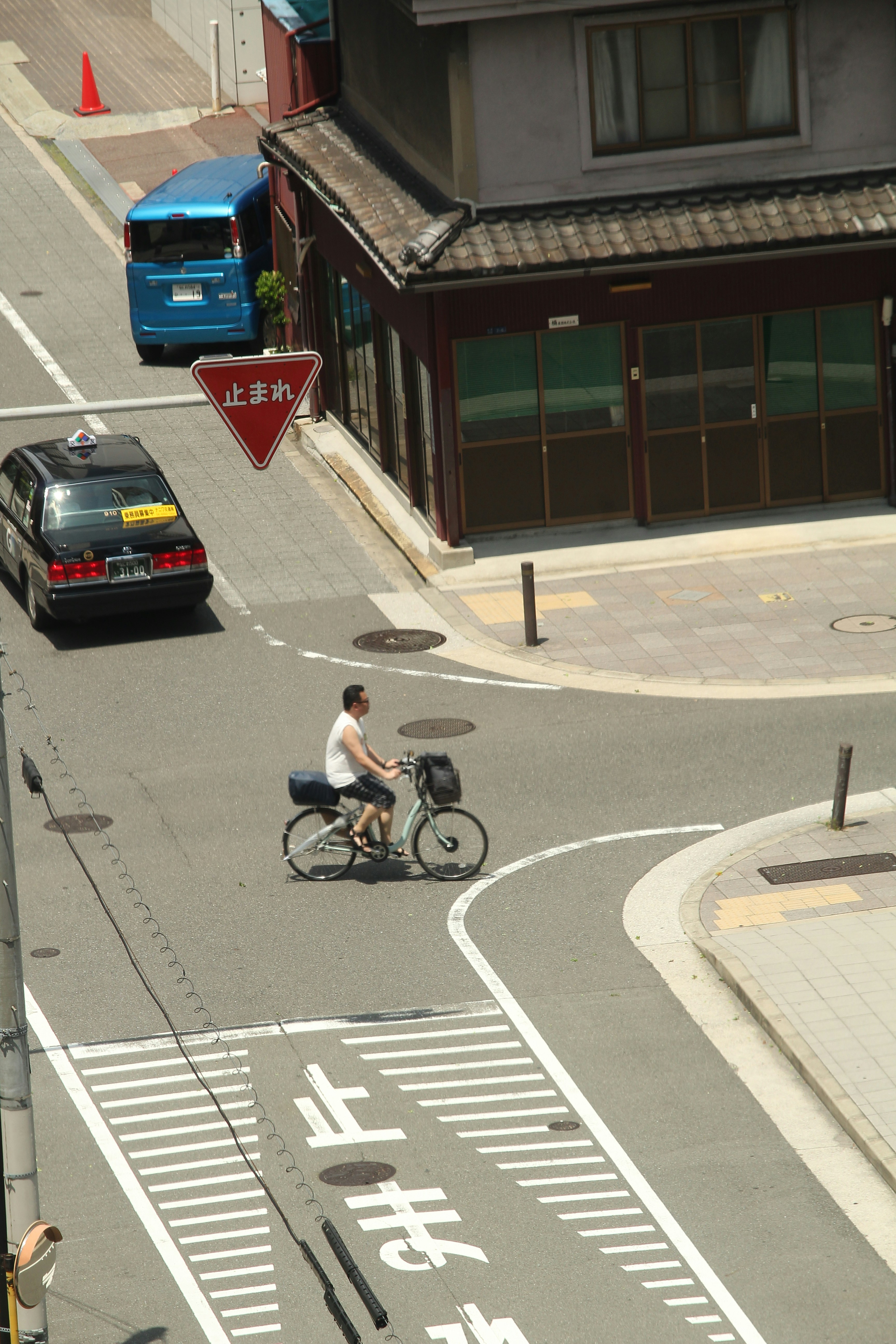 Cyclist at a Quiet Intersection Beneath a Japanese Street Corner