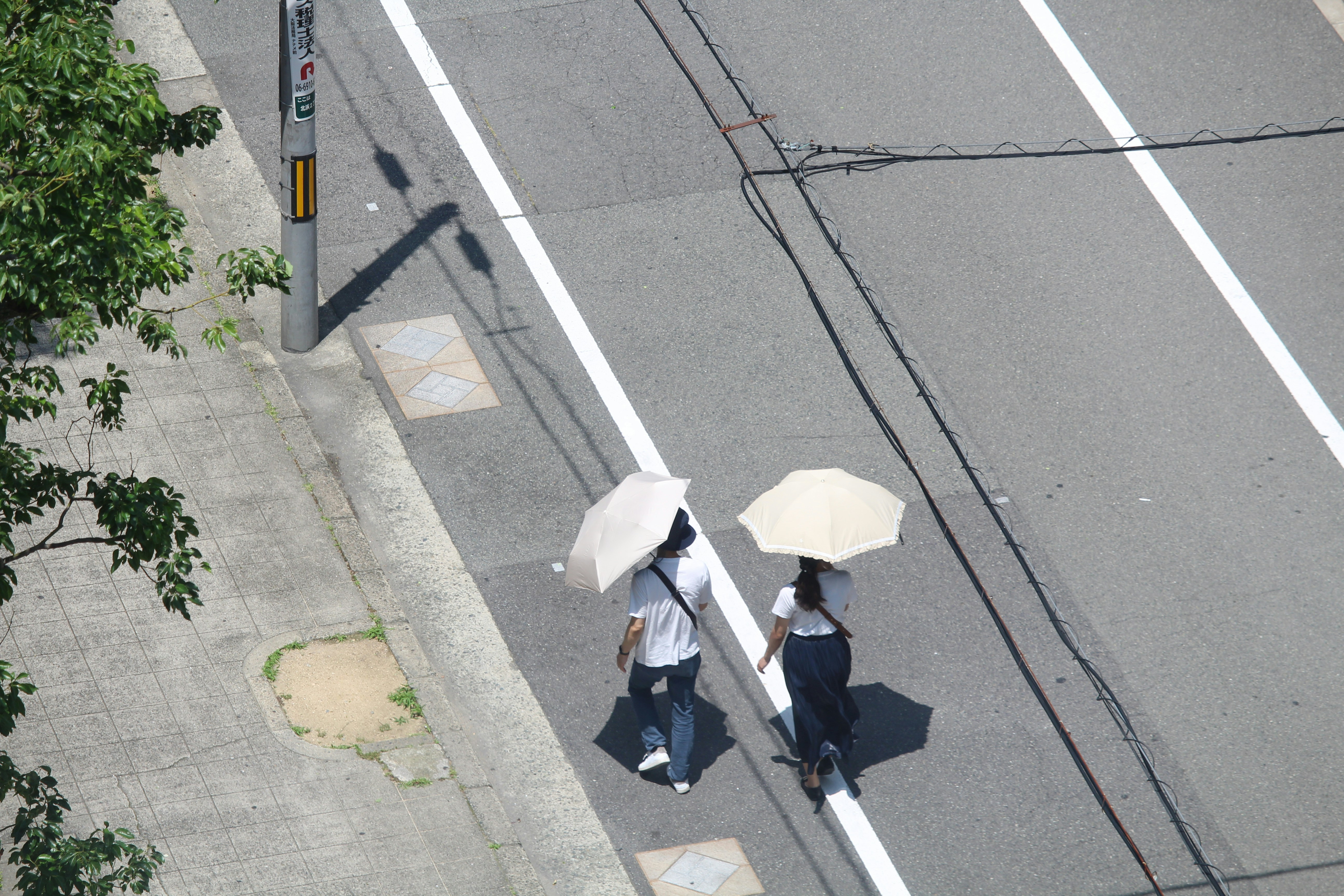 Umbrella Walk: Sunlit Street Sepia of Two Pedestrians