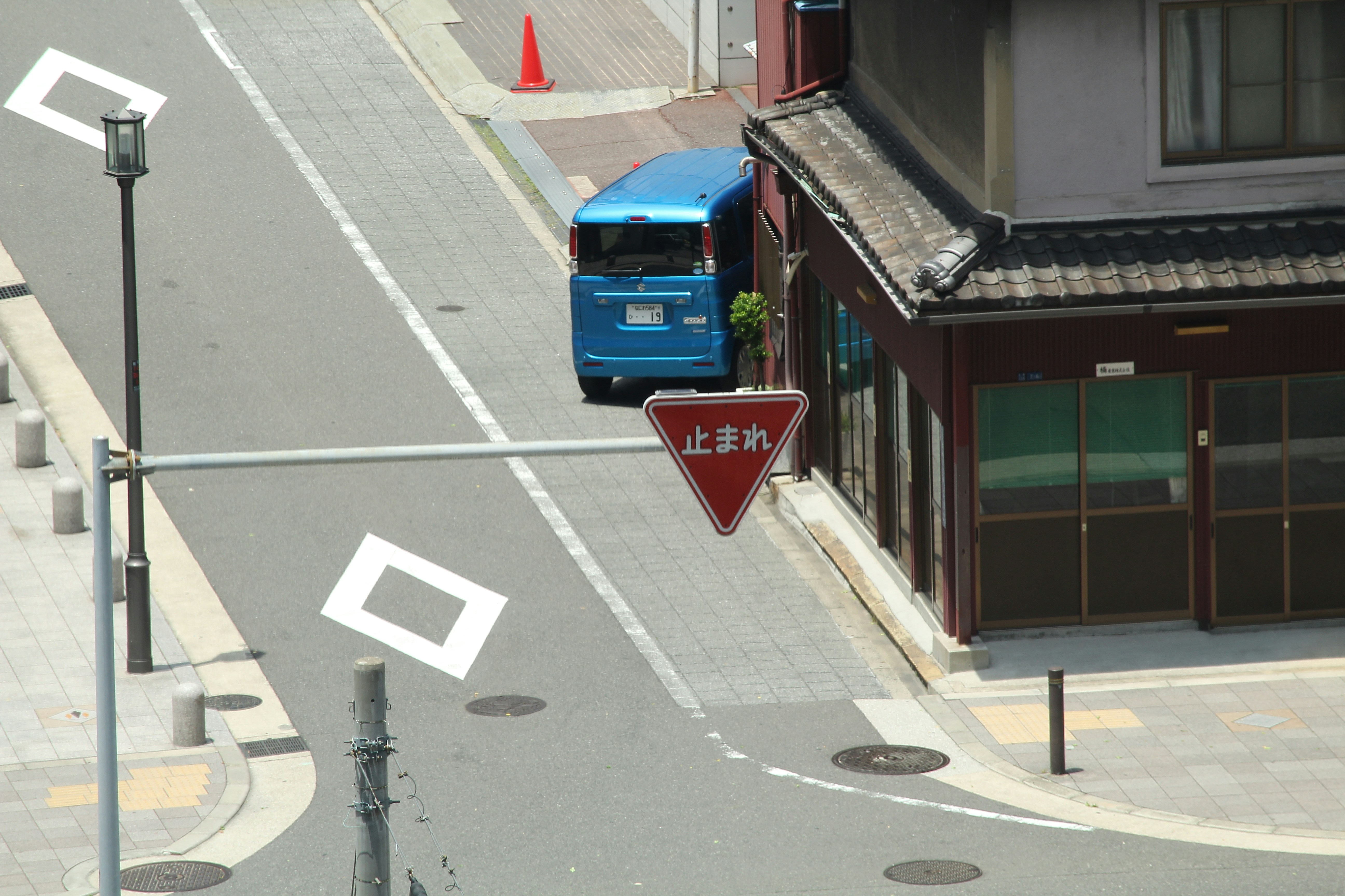 Blue van at a quiet street corner framed by traditional storefronts