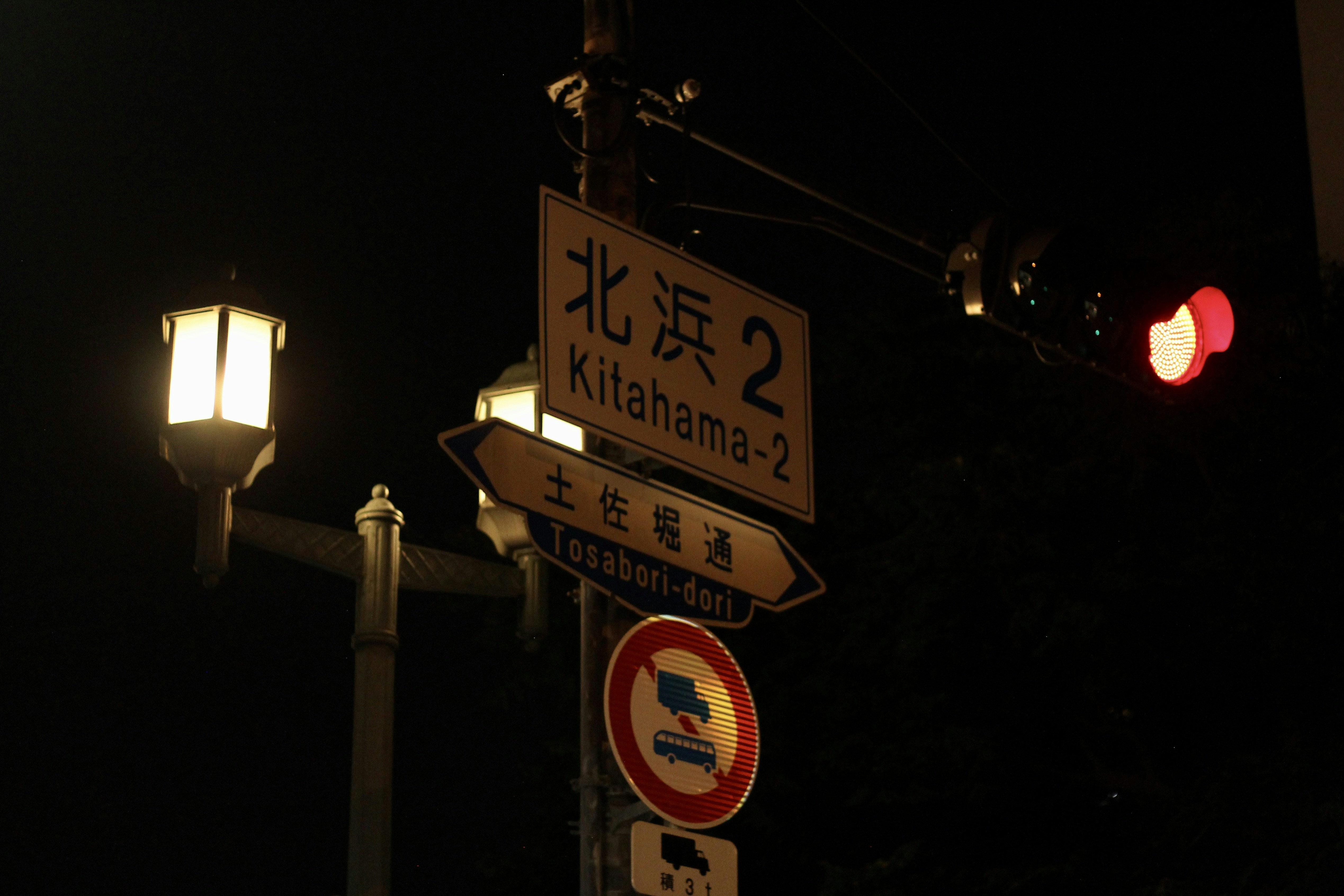 Nighttime Japanese Street Sign Under Warm Streetlamp glow