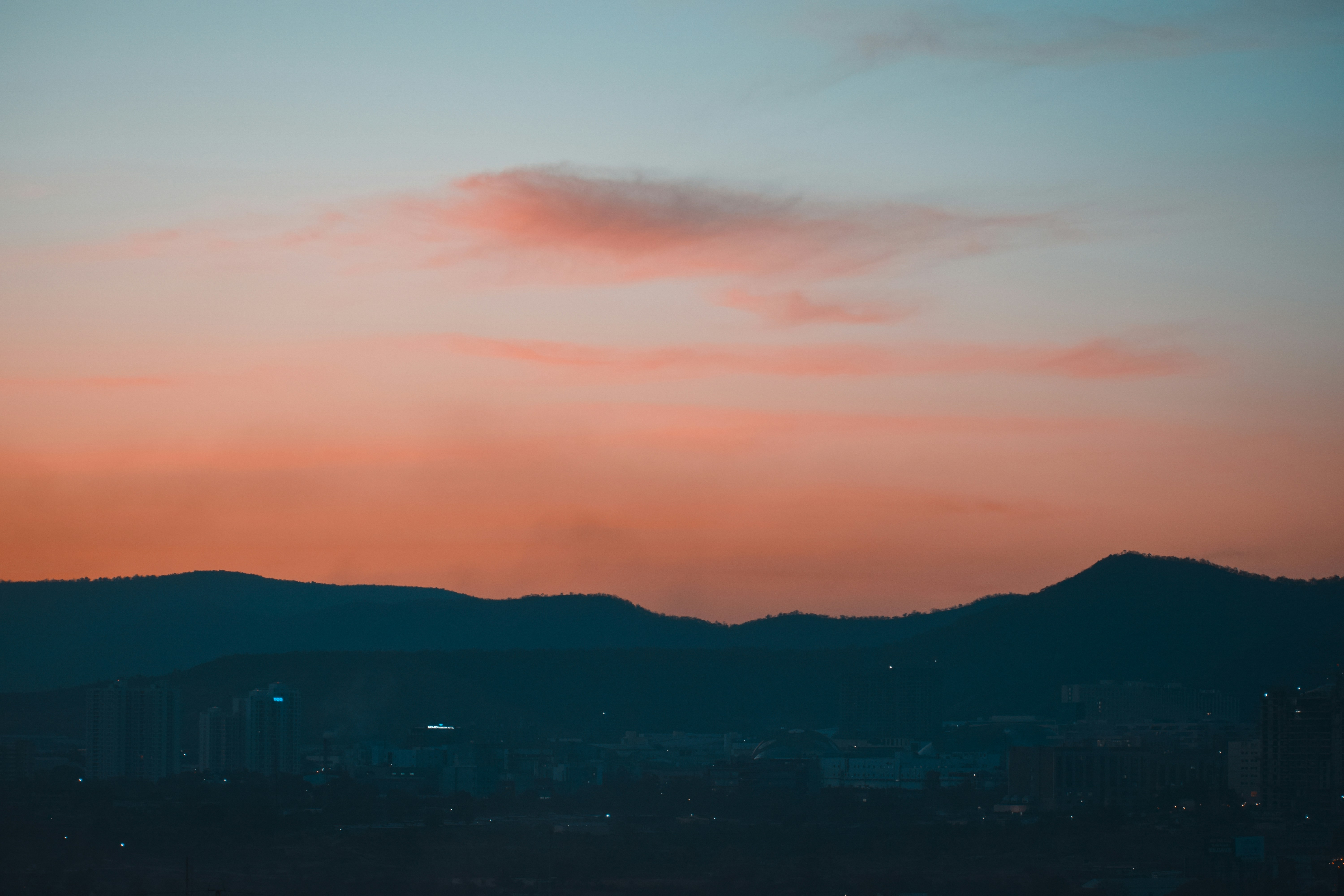 Twilight Ridge: A Quiet City Silhouette Beneath a Coral Sky