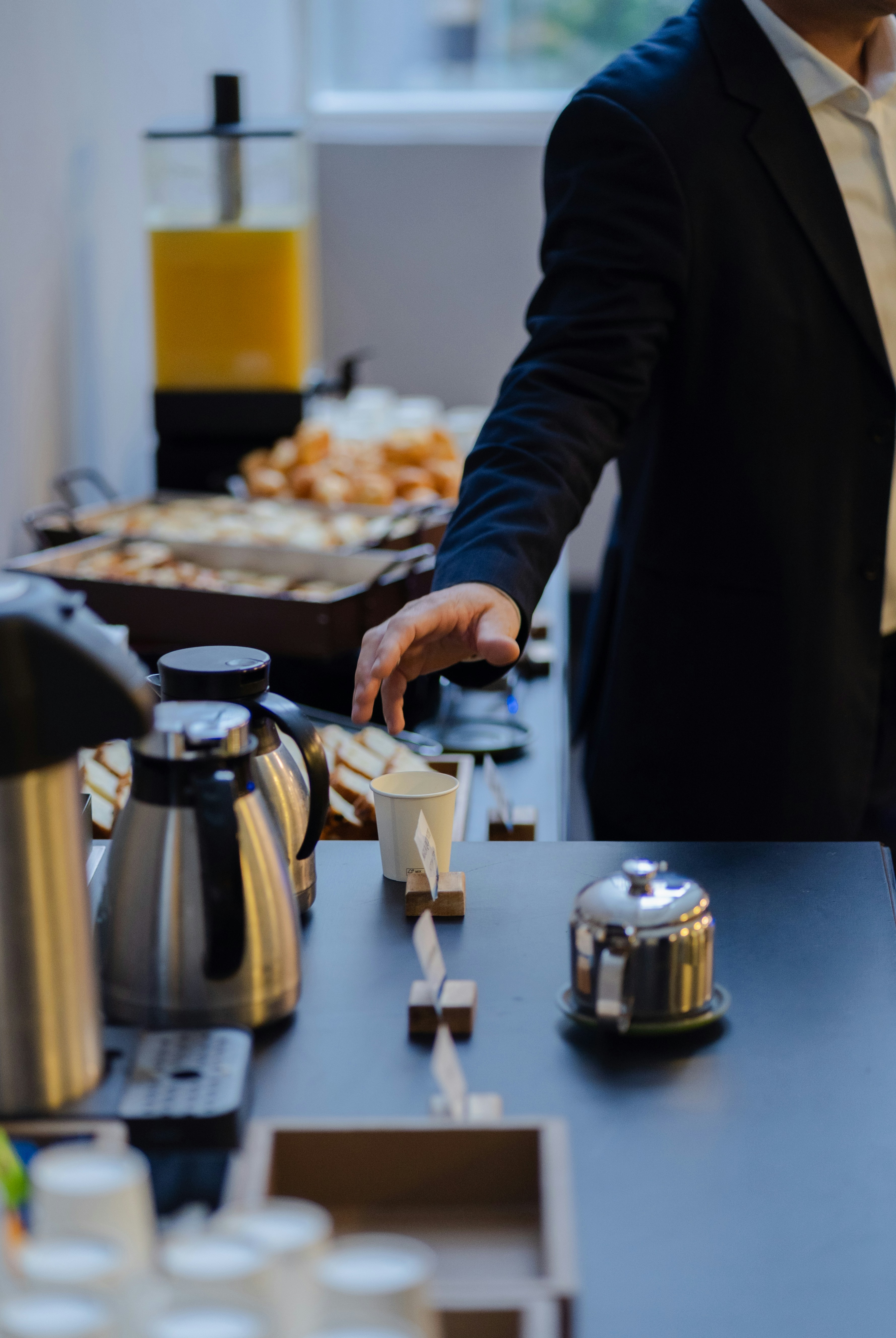 Hand reaching for a coffee cup at a breakfast spread.