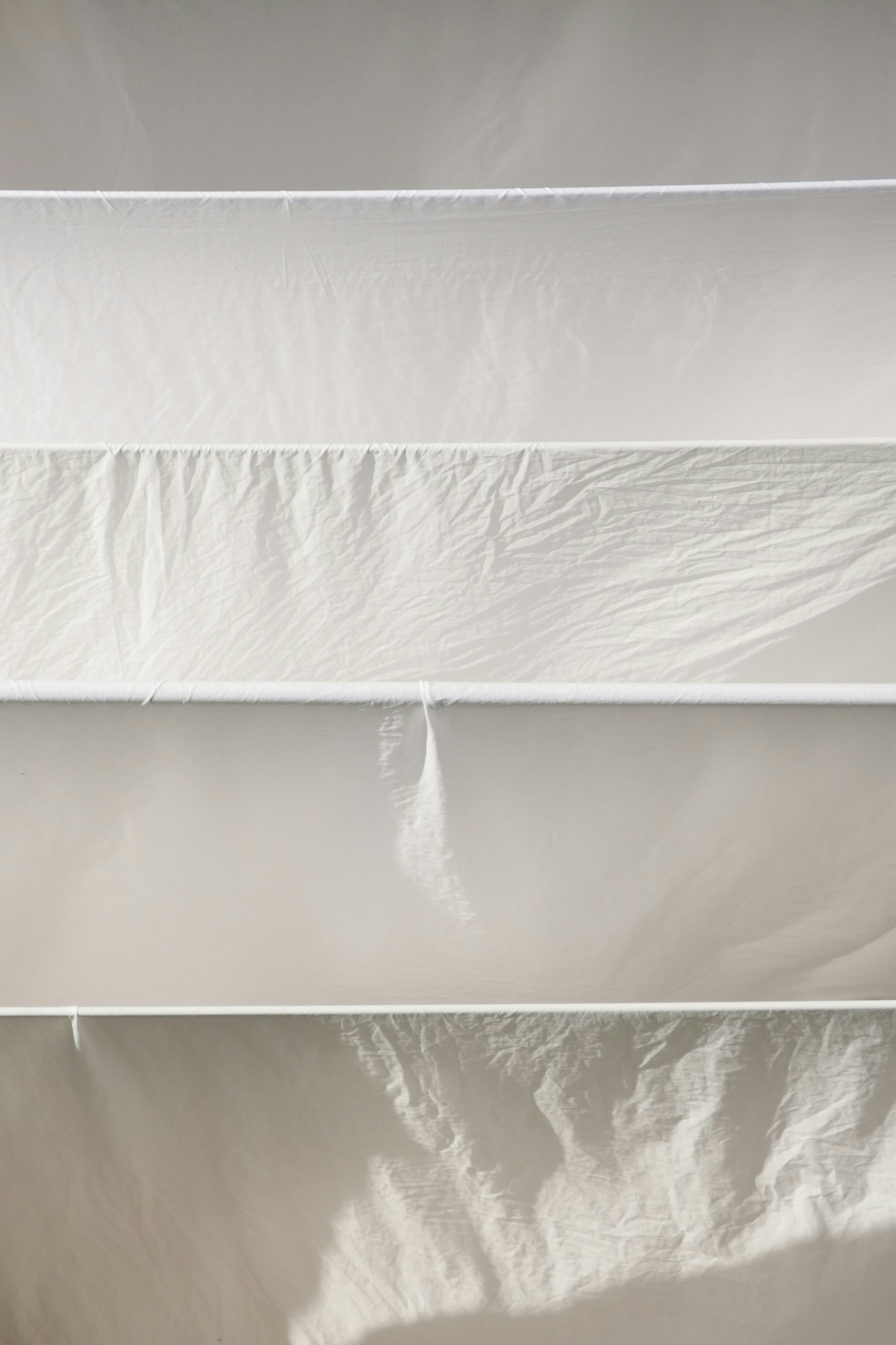 Layered Tension: Sun-bleached Fabric Ribbons Across Horizontal Strata