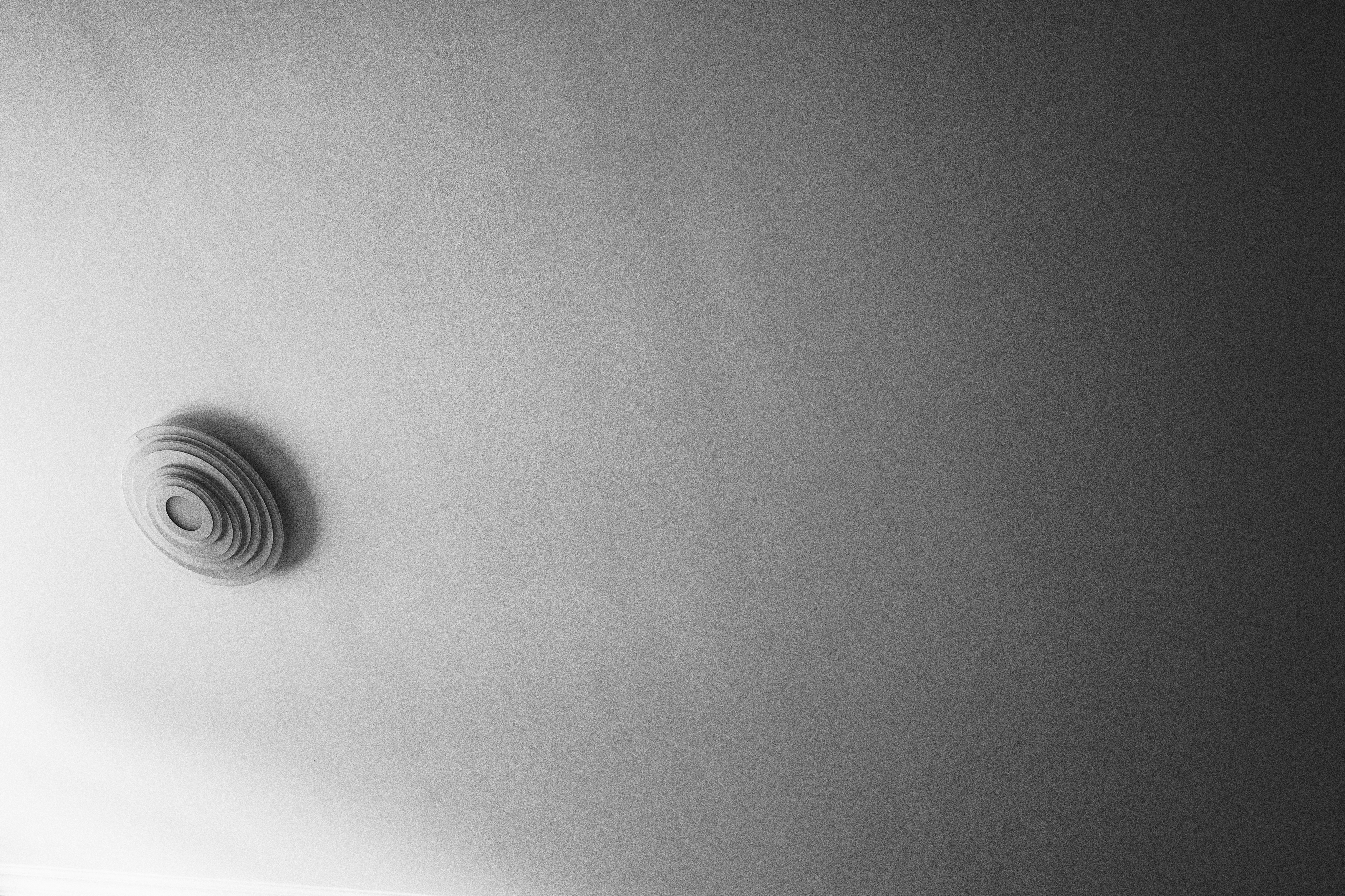 Minimalist grayscale wall with a spiral doorstop near the left third, creating subtle texture and shadows.