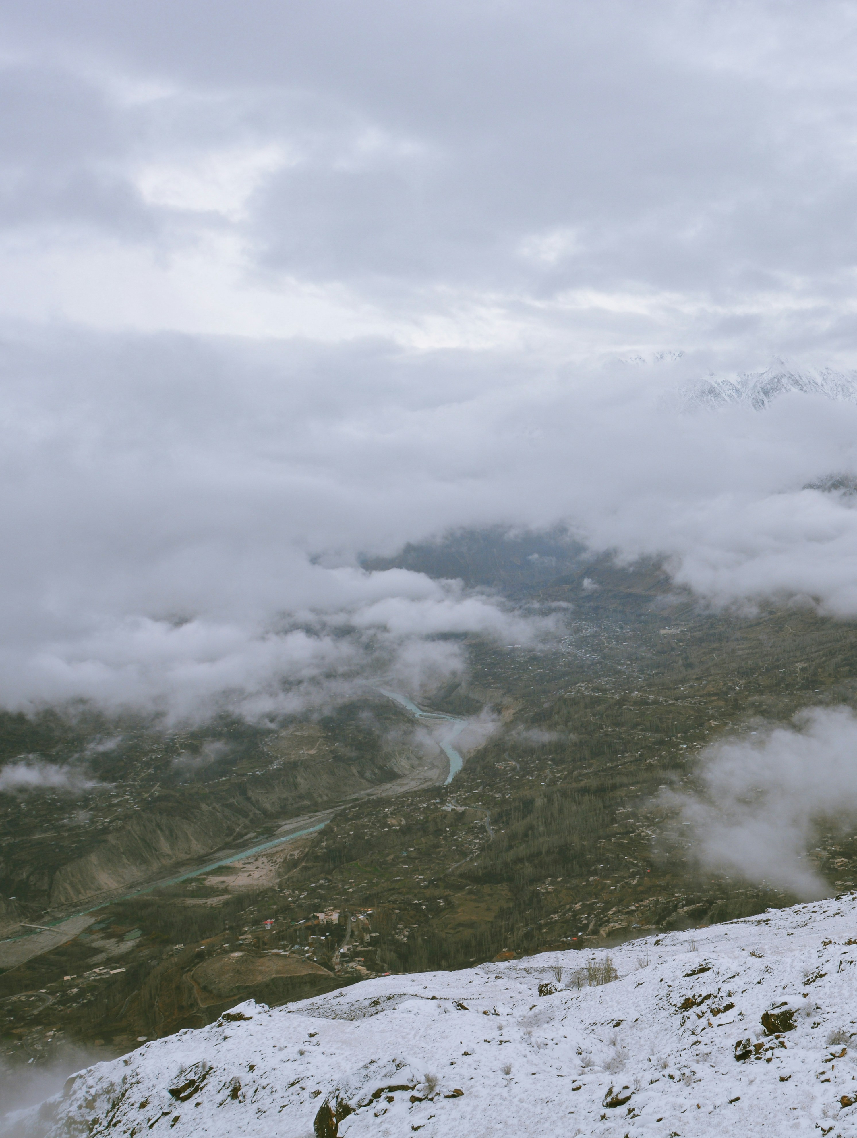 Snow-Kissed Ridge Overlooking a Valley Veiled in Clouds