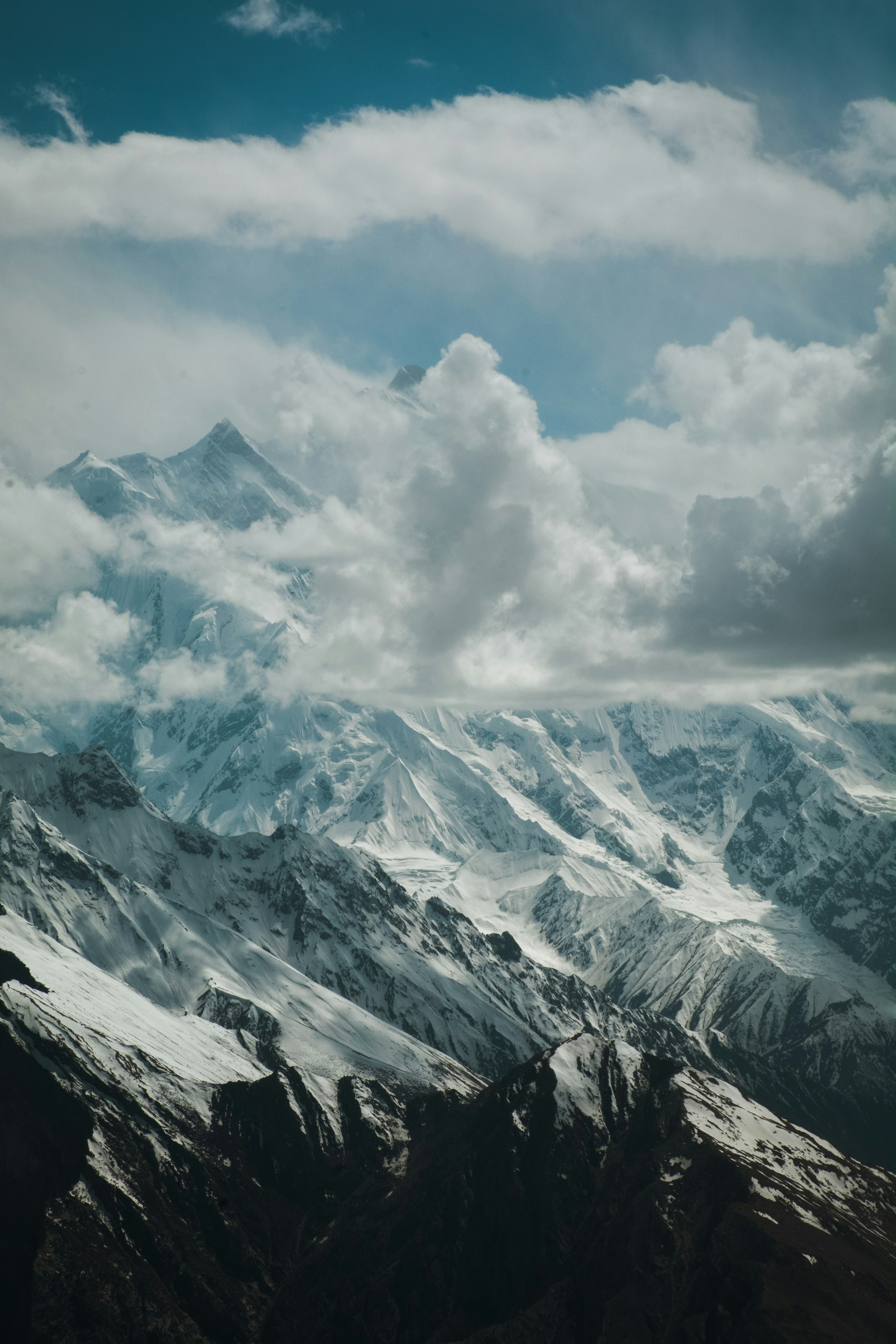Snowy mountain range under dramatic clouds, with sunlit peaks and shadowed valleys.
