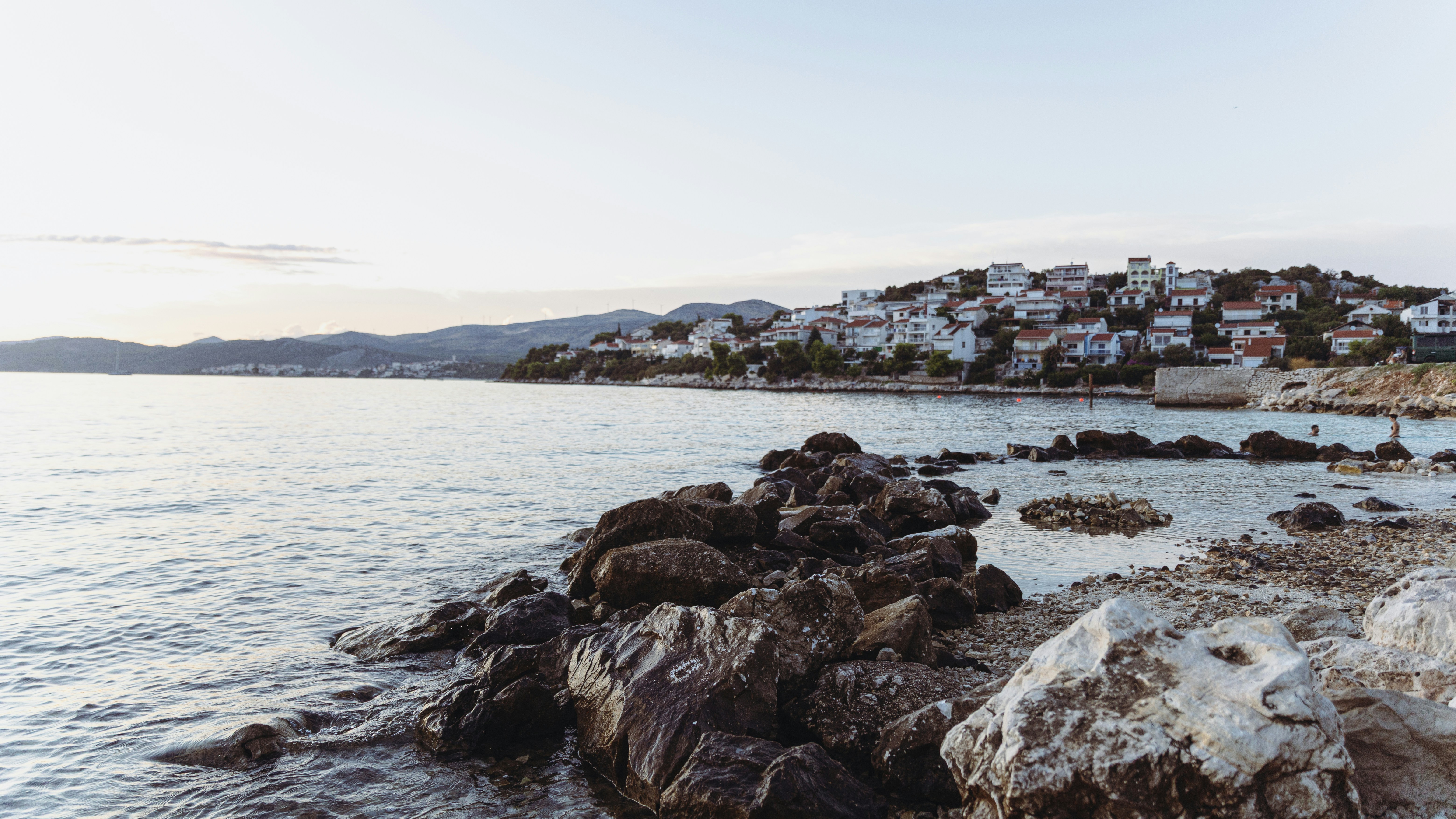 Rocky promontory meeting the town: sunlight catching the breakwater and harbor homes
