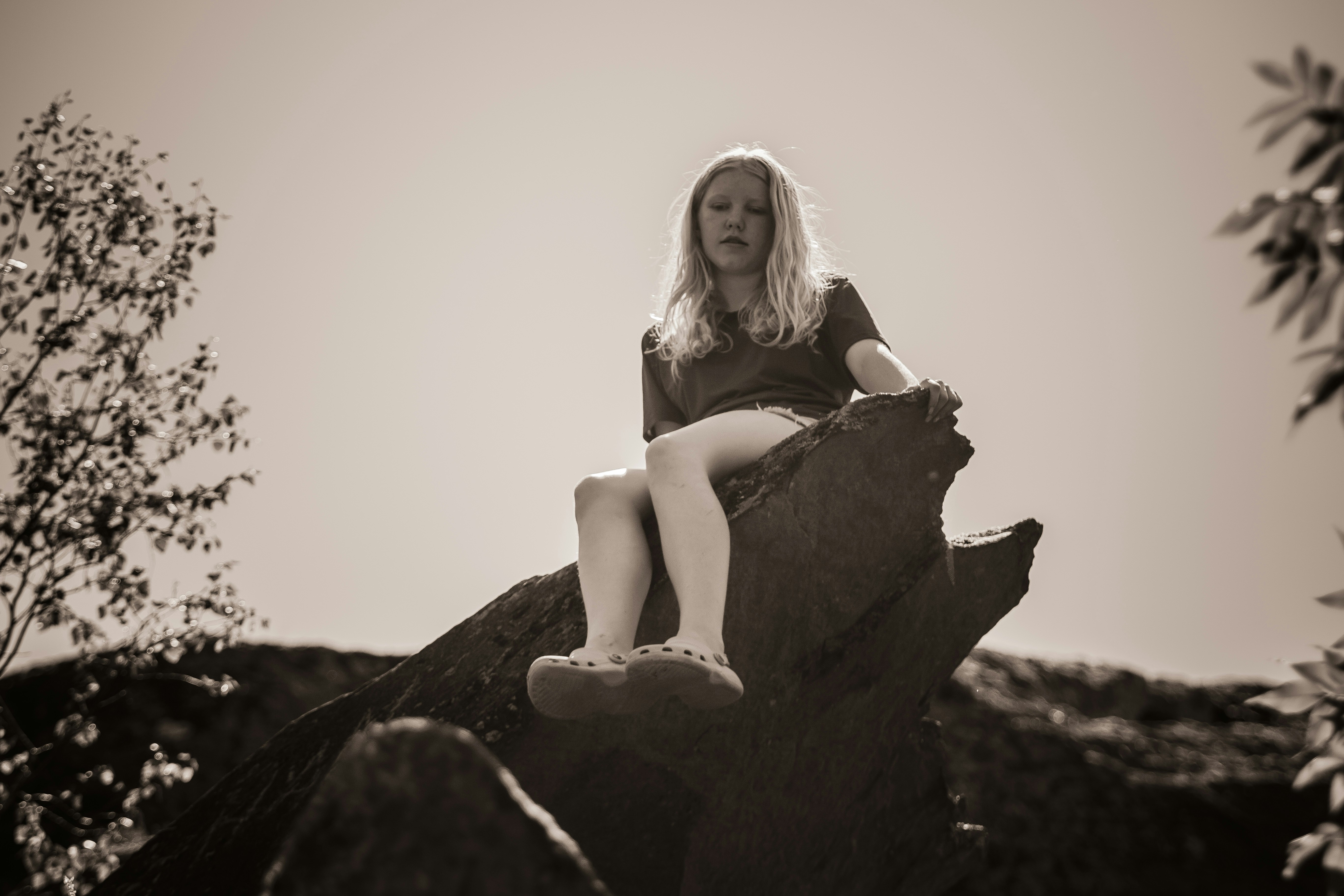 Solitary Repose: A Girl Perched on Stone Under a Quiet Sky