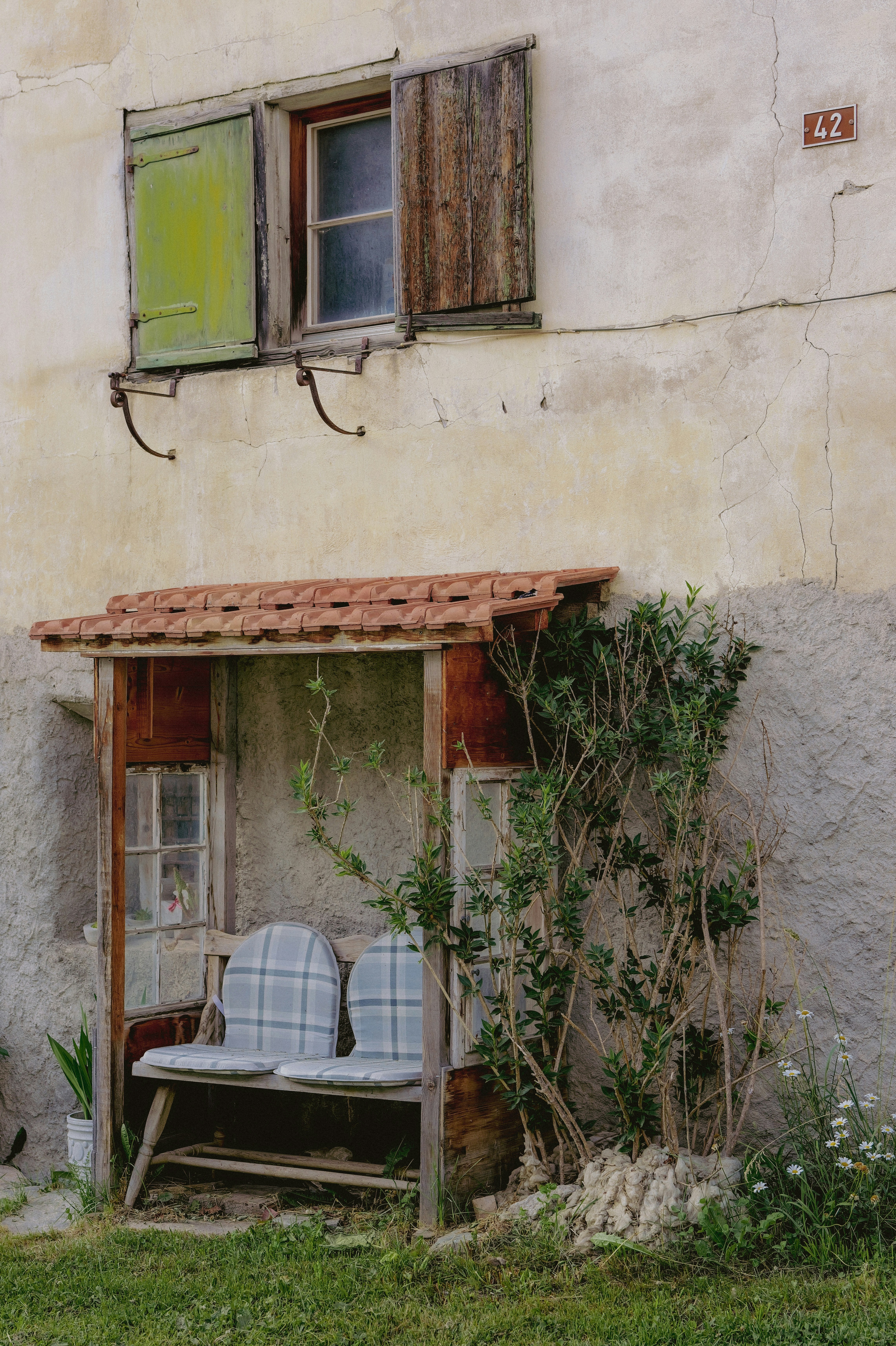 Weathered villa with a vine-draped porch and peeling shutters