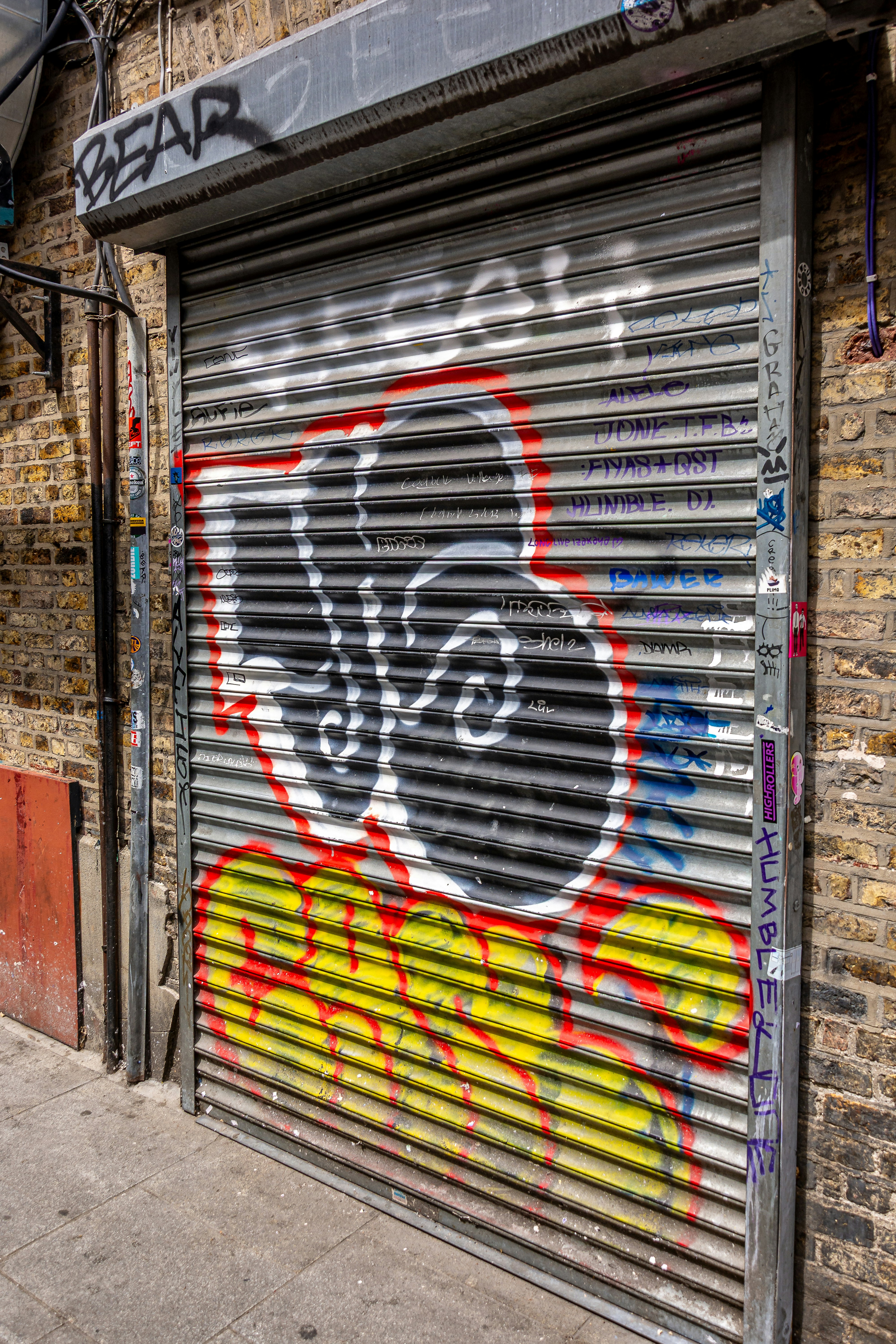 Concrete Canvas: A Graffitied Roll Gate Abloom with Bold Black, Red, and Yellow Forms