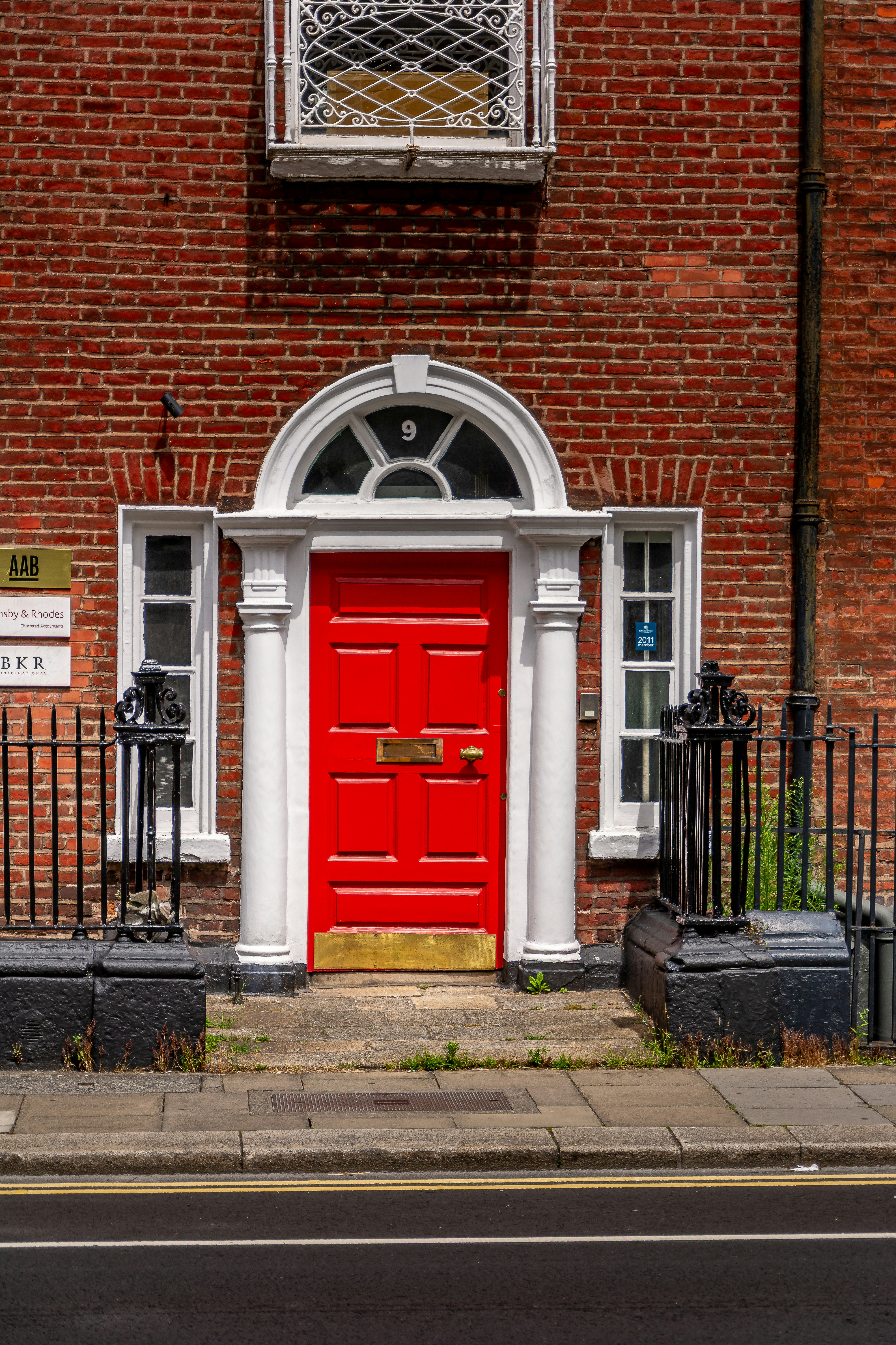 Crimson Doorway: A Red Entrance Framed by White Columns on a Brick Facade