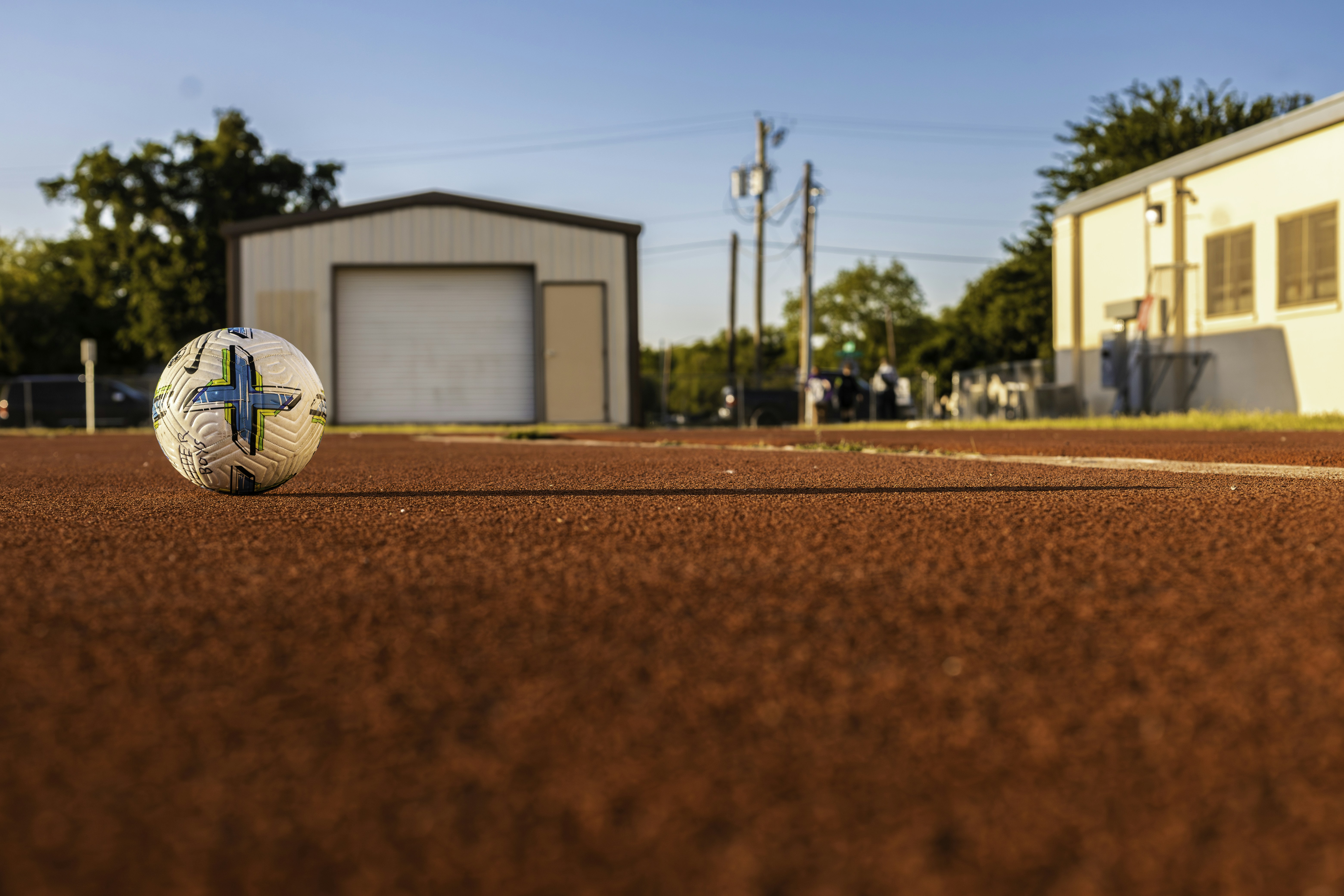 Low Shot Then Play: A Solo Soccer Ball on a Warm-Red Track
