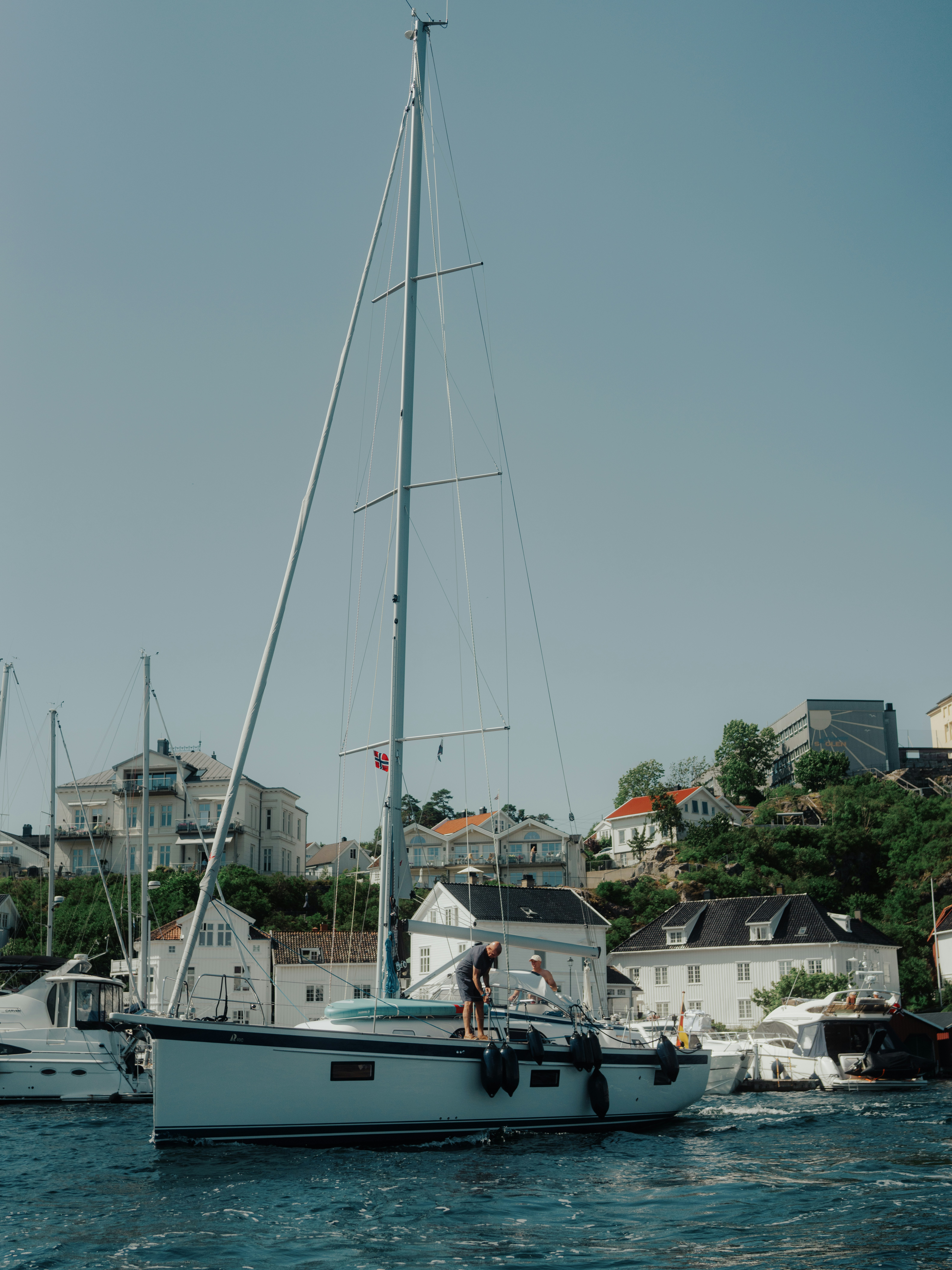 Sailboat at moor in a sunlit harbor, town rising behind