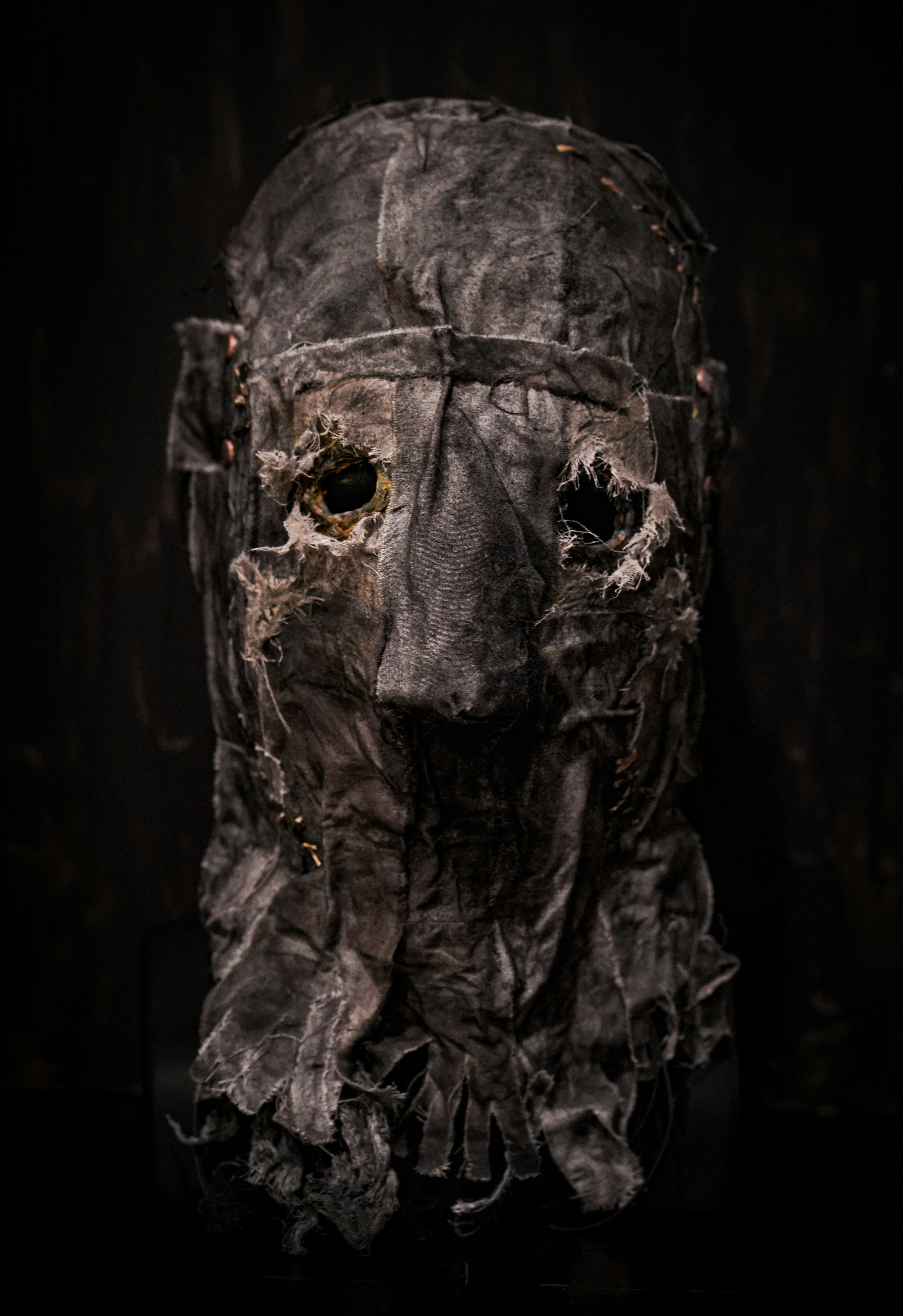 The Worn Vigil: A Shrouded Mask in Dim Light