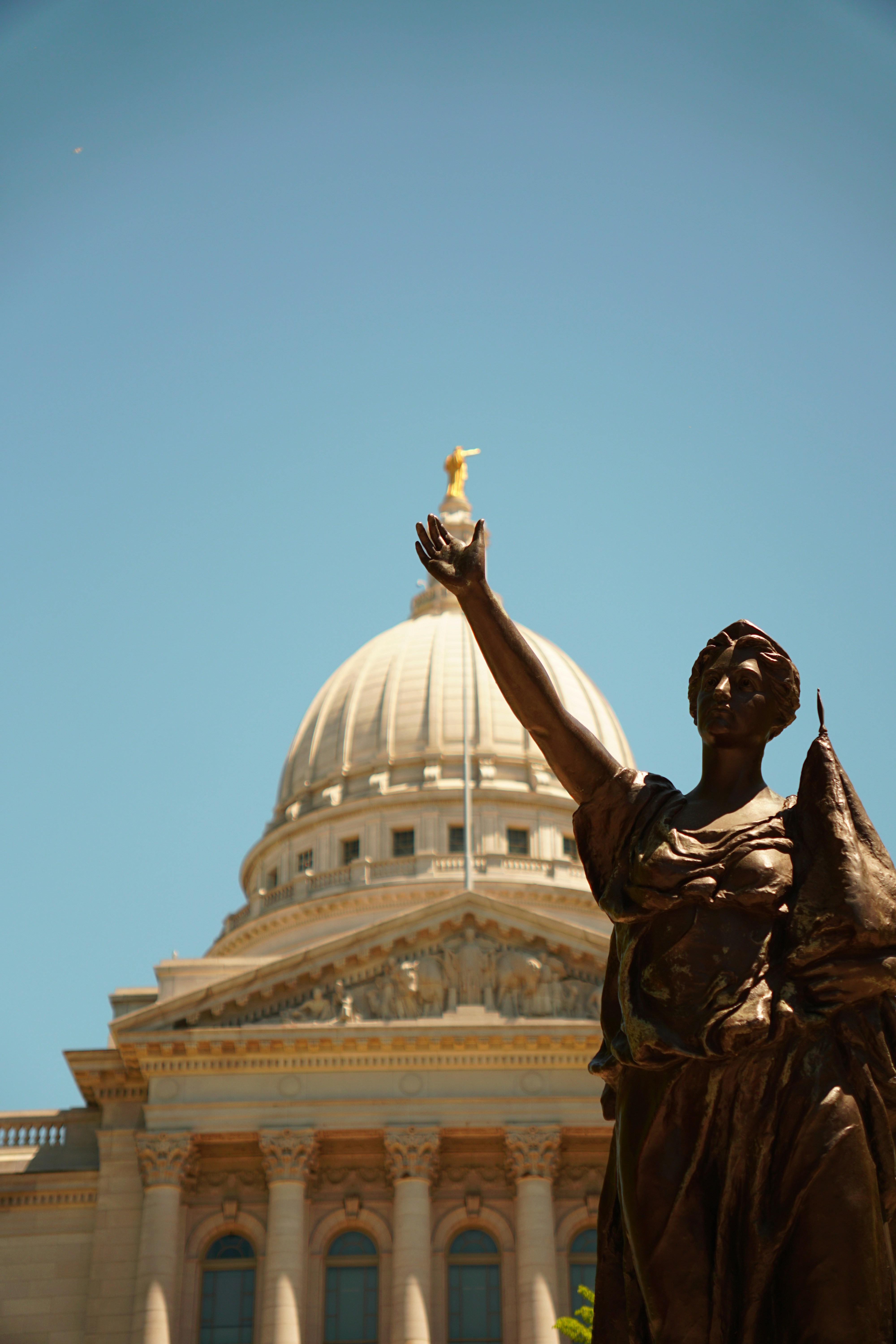 Raised Arm and Statuary: A City Dome Behind