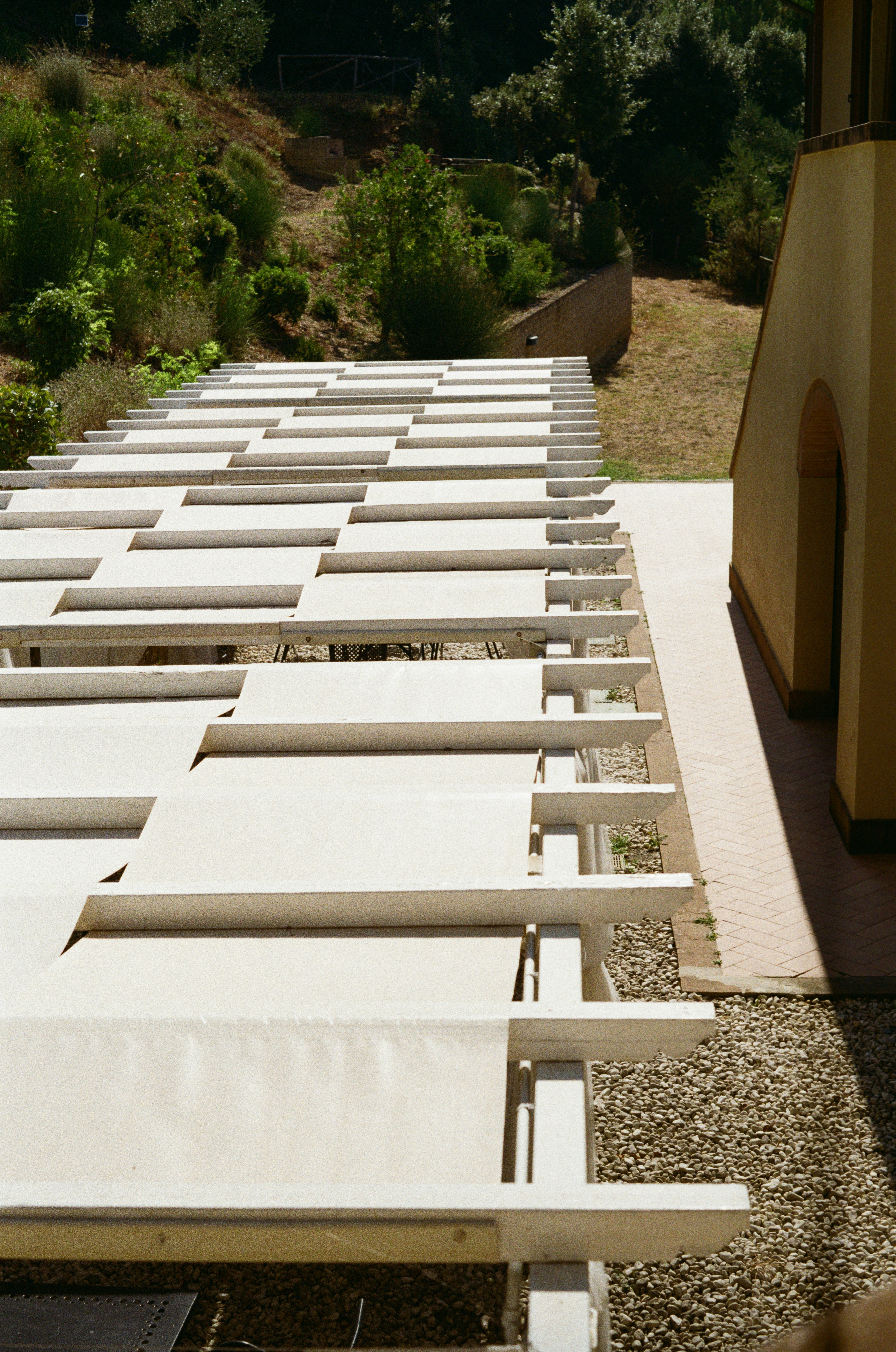 Rows of white pergola shadows march toward the terrace arch