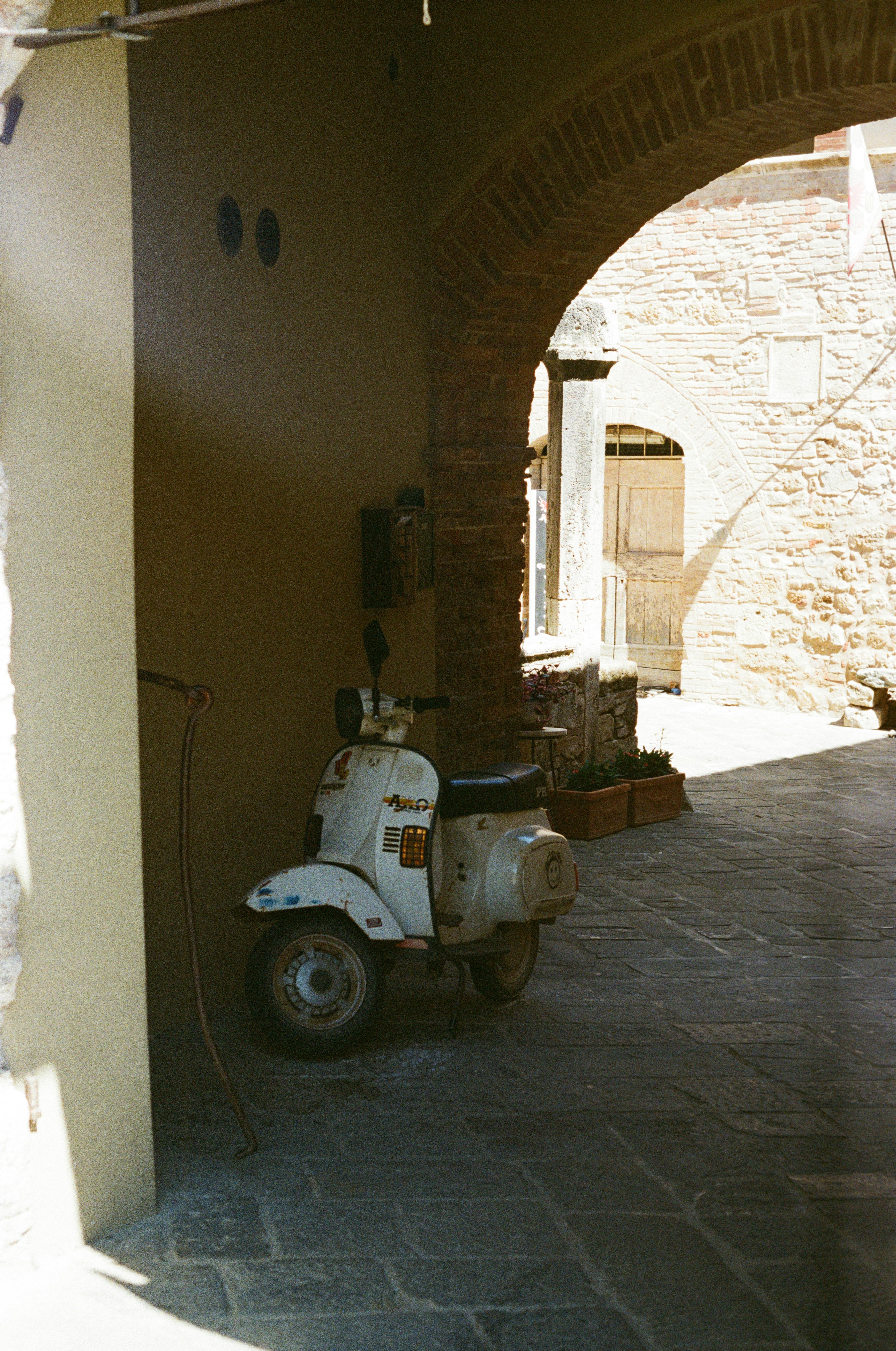 Quiet Passage: A Vespa Nestled Under Stone Arches