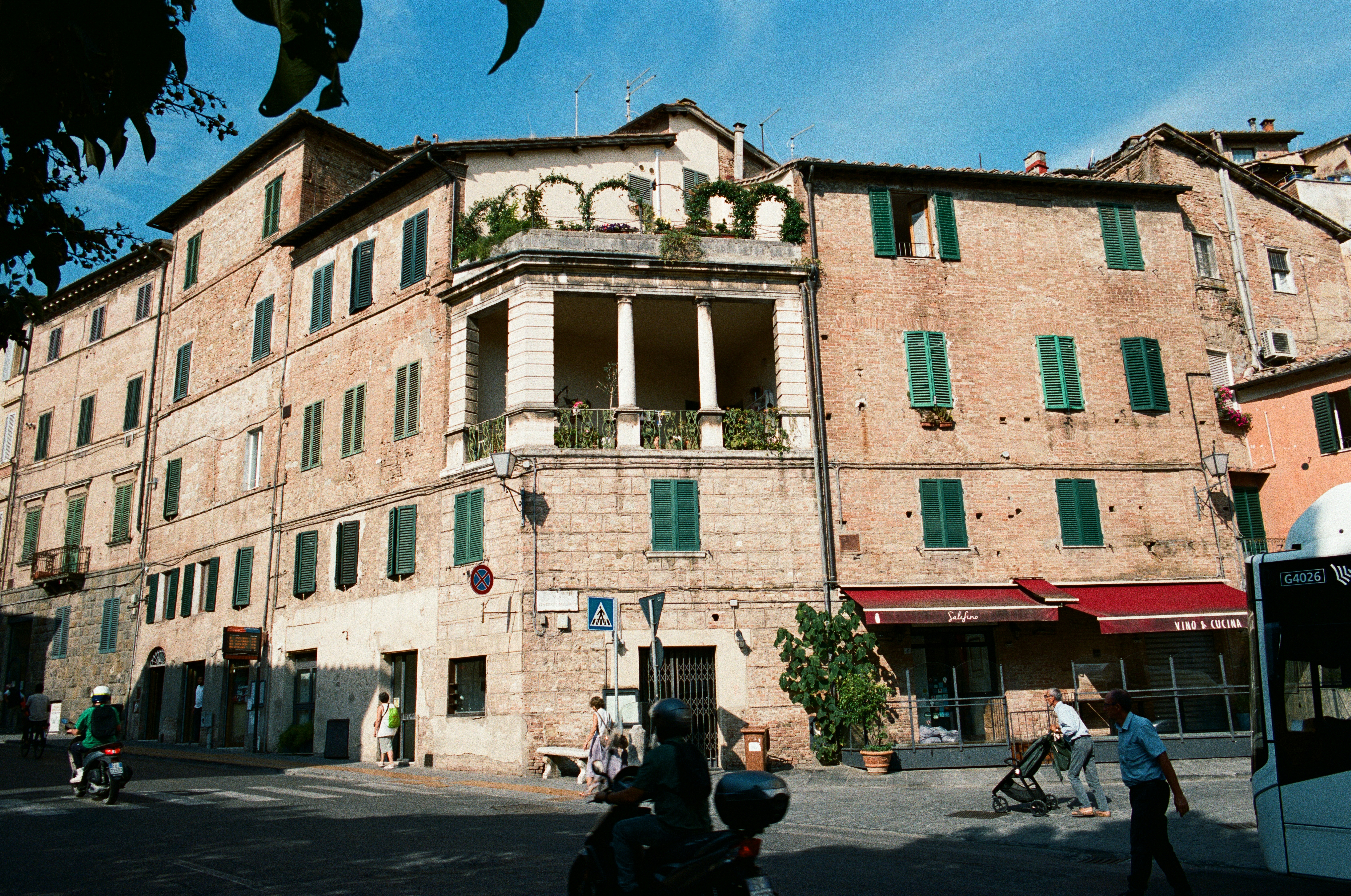Sunlit Italian Streetfront with Aged Facade and Tranquil Activity