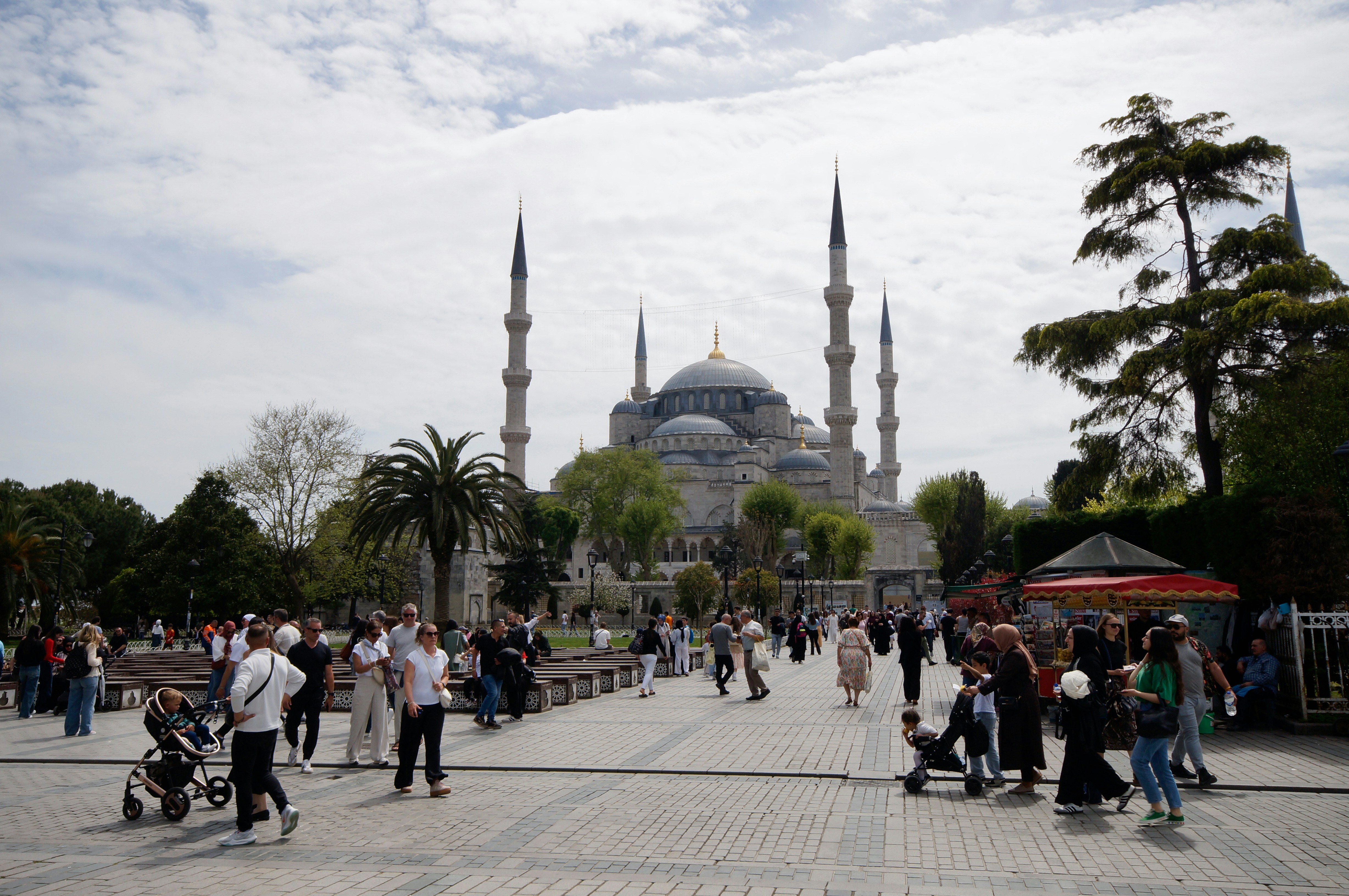 A bustling square with visitors and families in front of the Blue Mosque, capturing public life and the historic skyline.