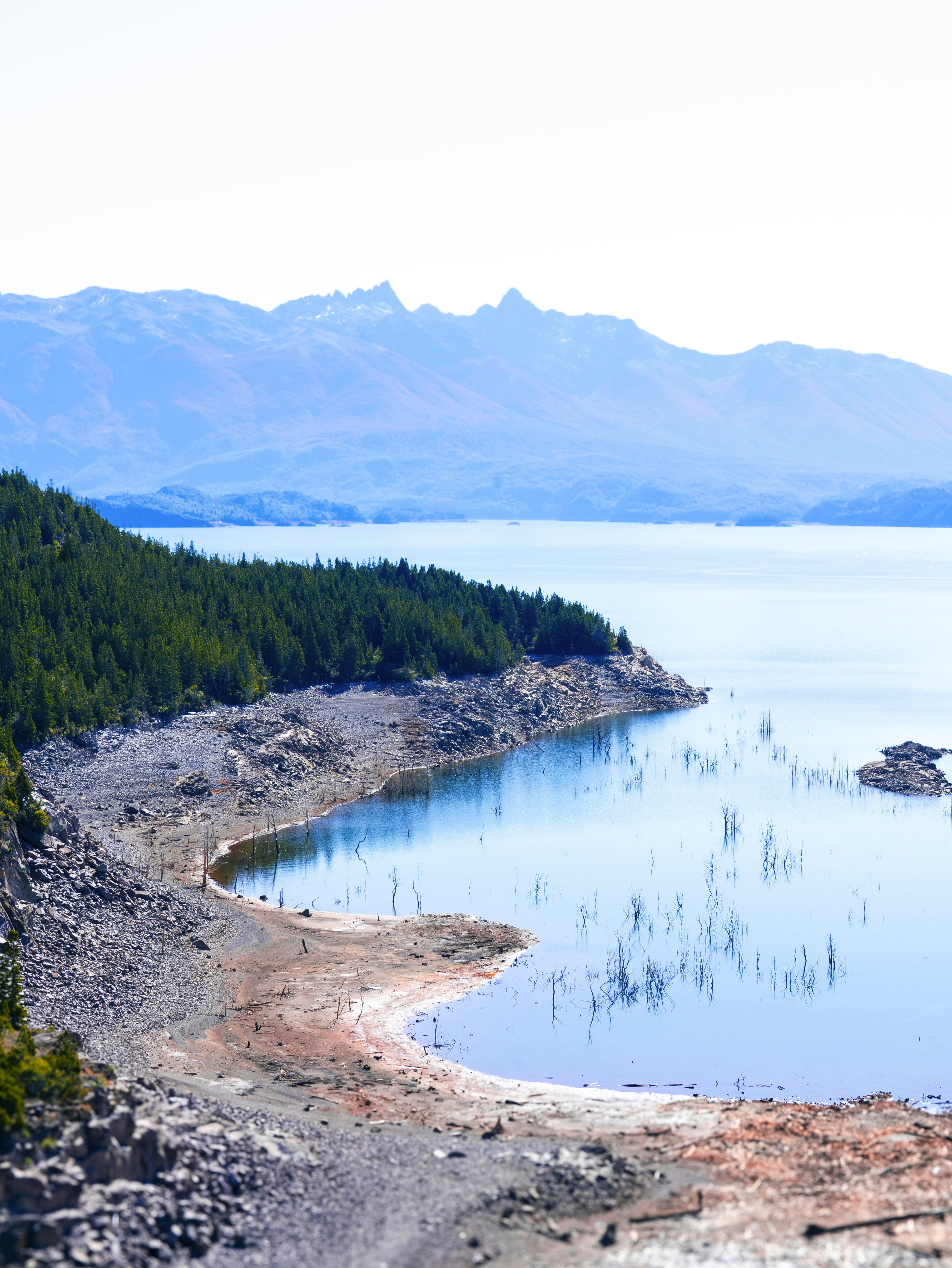 Curved shoreline and blue fjord under a distant alpine horizon