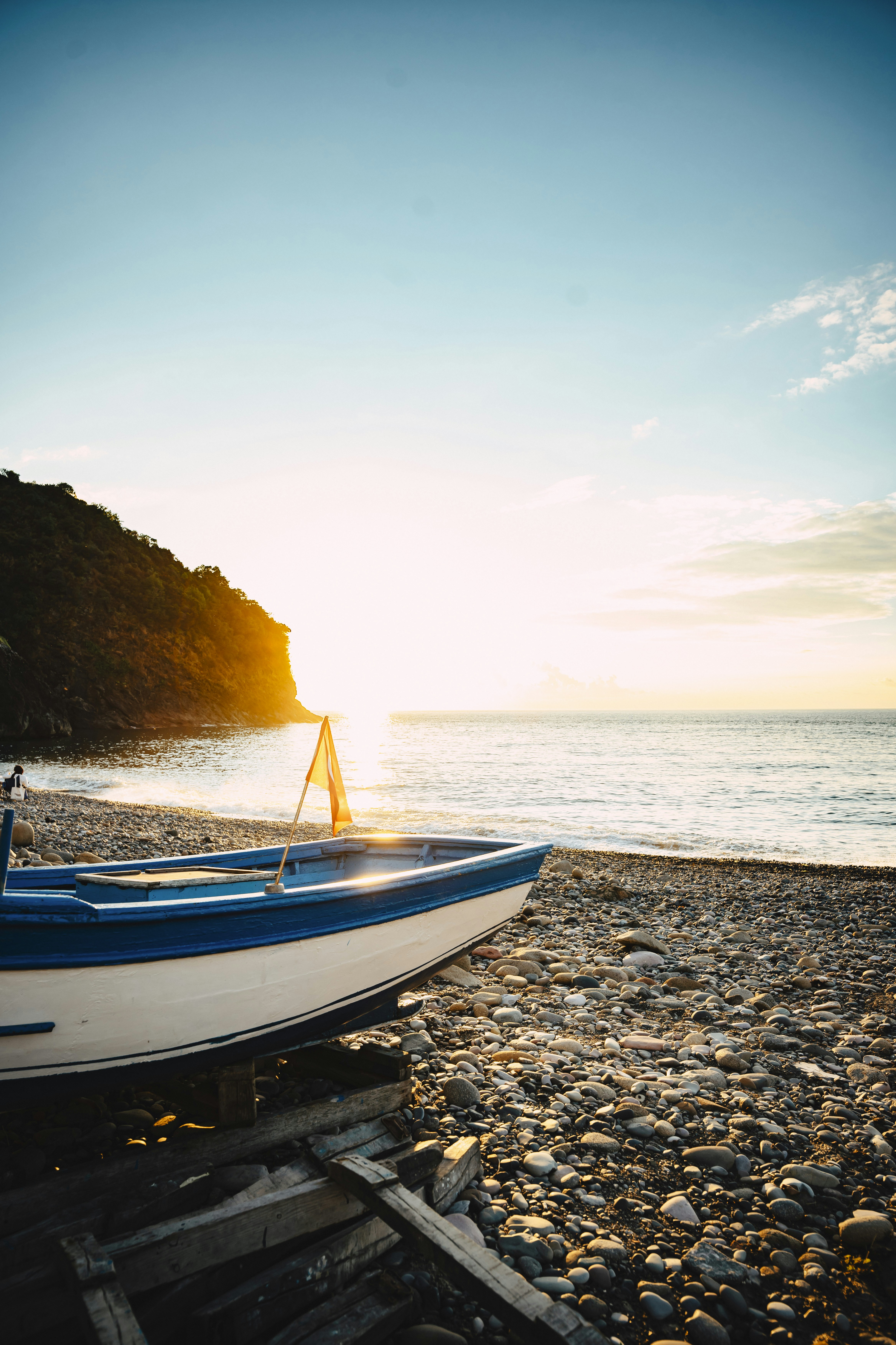 Sunlit Boat Resting on a Pebble Shore at Dusk