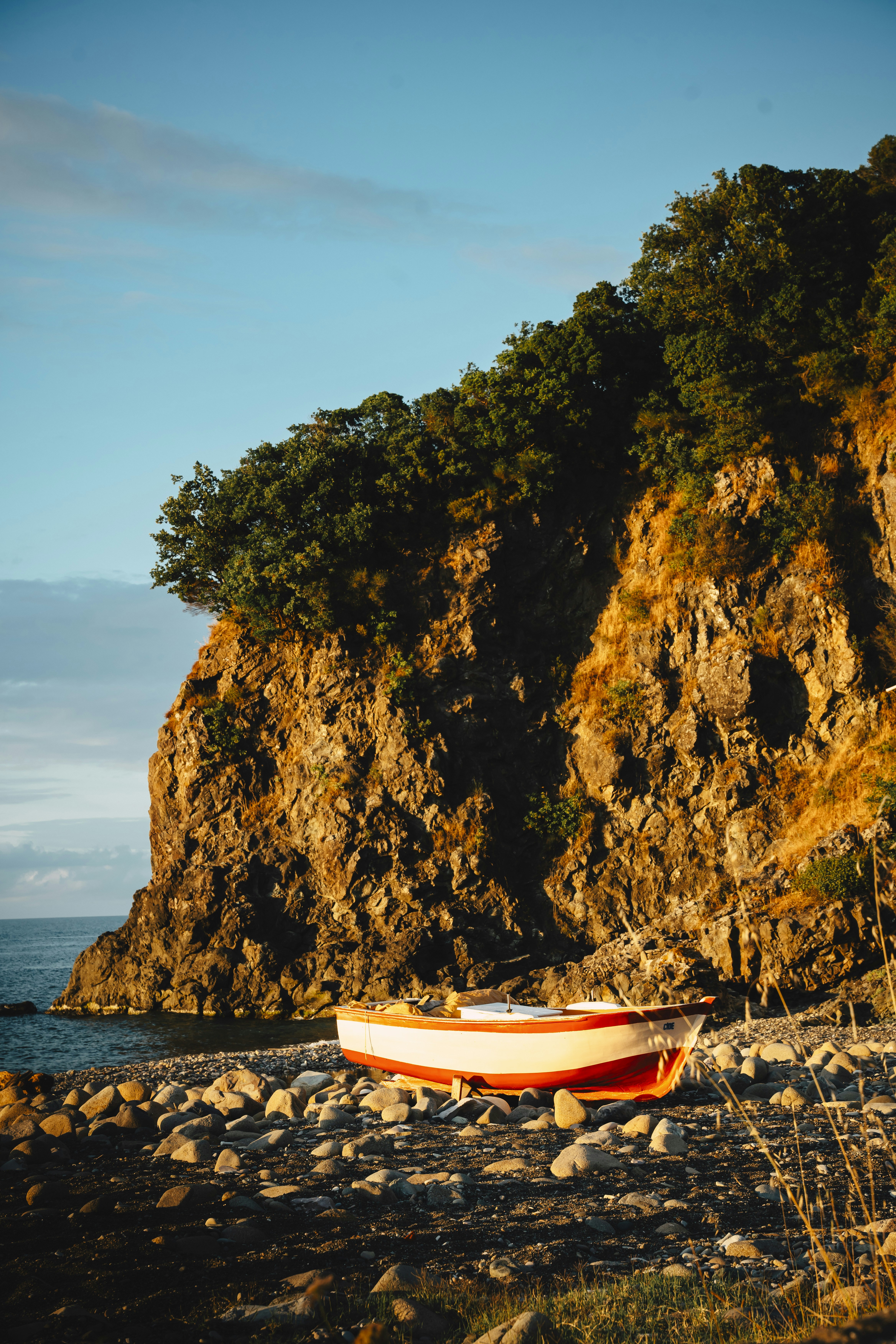 Stormlit Cliff and Boat on a Pebble Shore