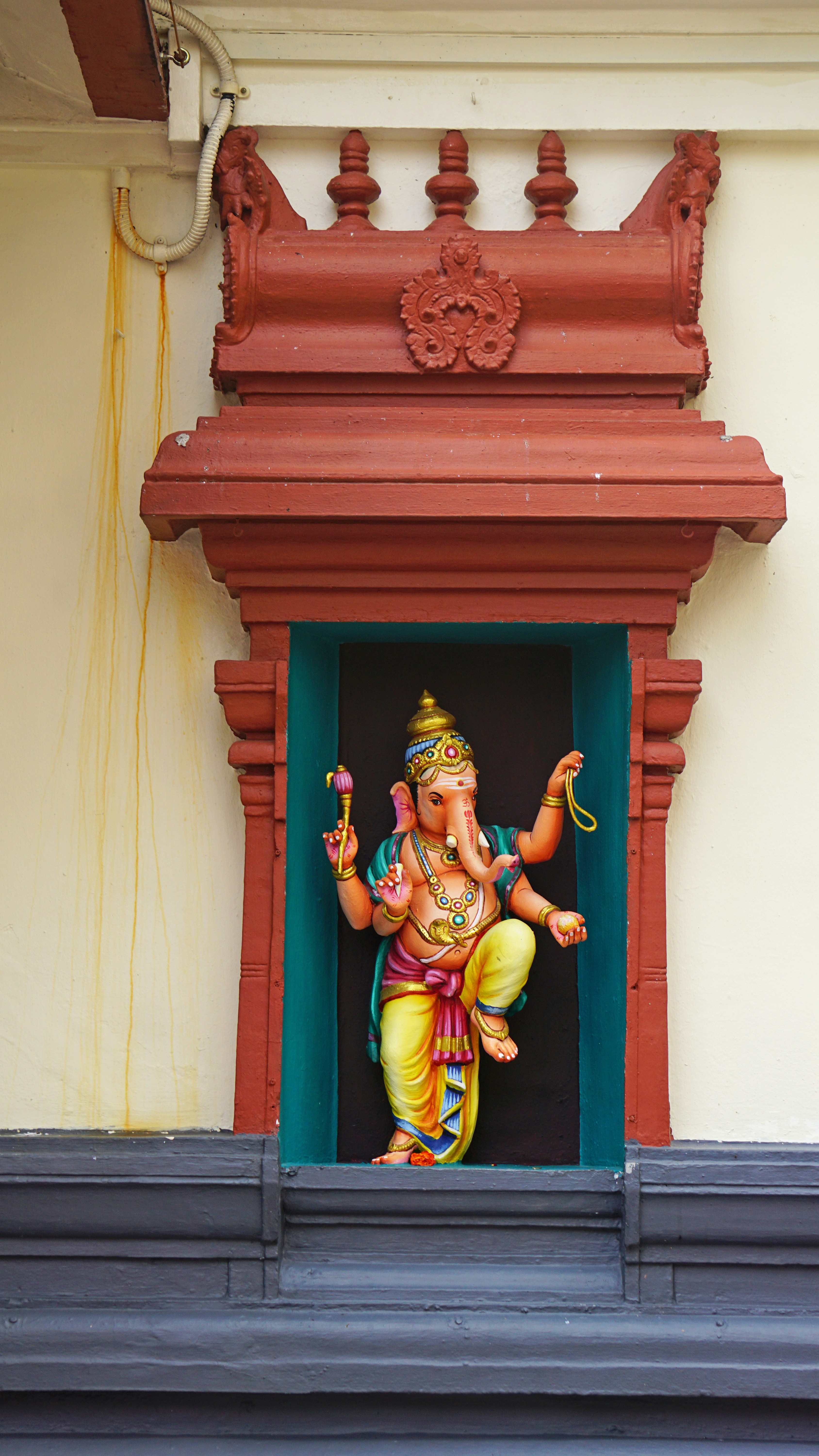 Divine Ganesha in a Painted Niche: A Shrine Portrait Framed by Red Ornamentation