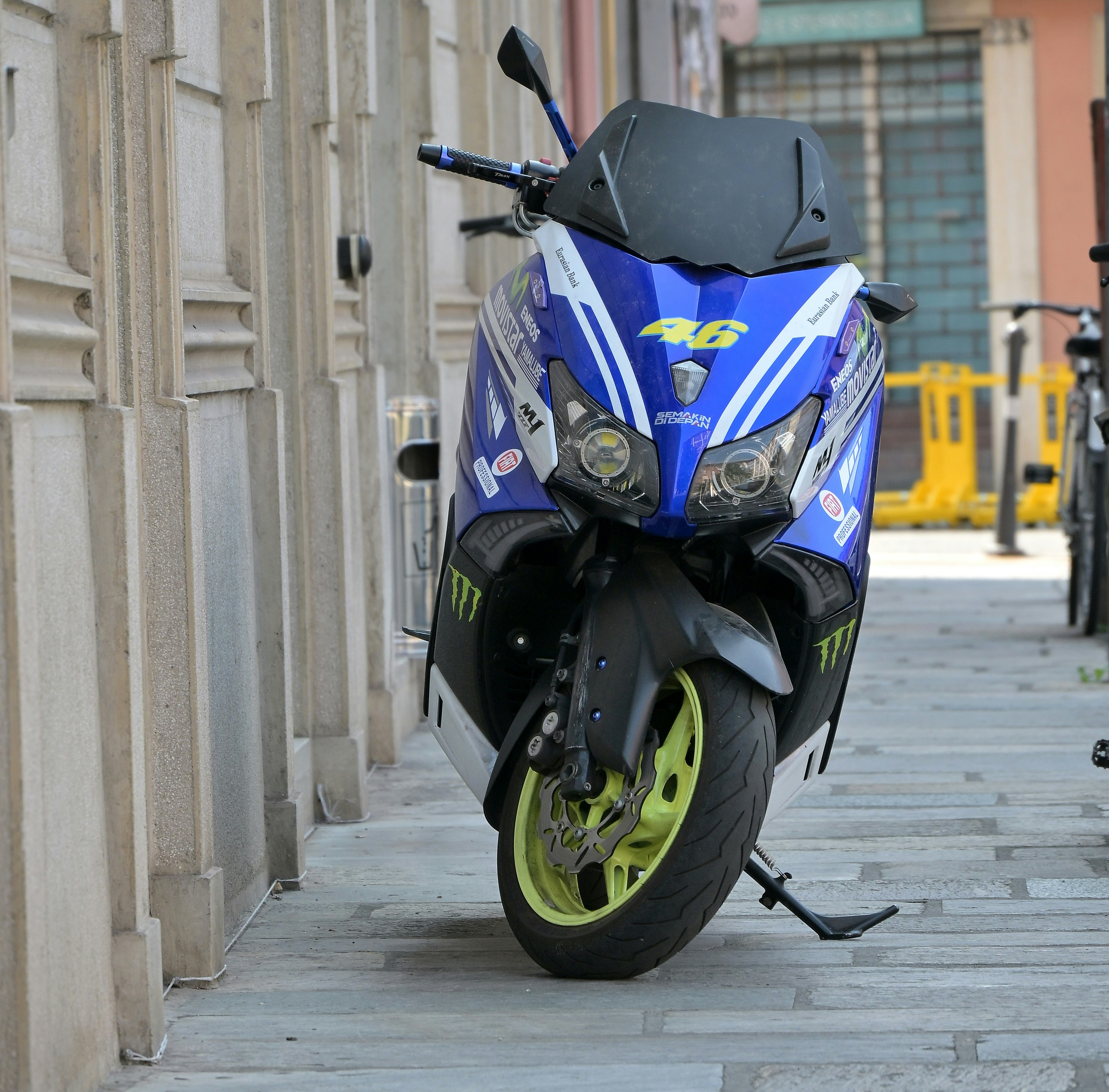 Blue racing scooter leaning against a stone wall