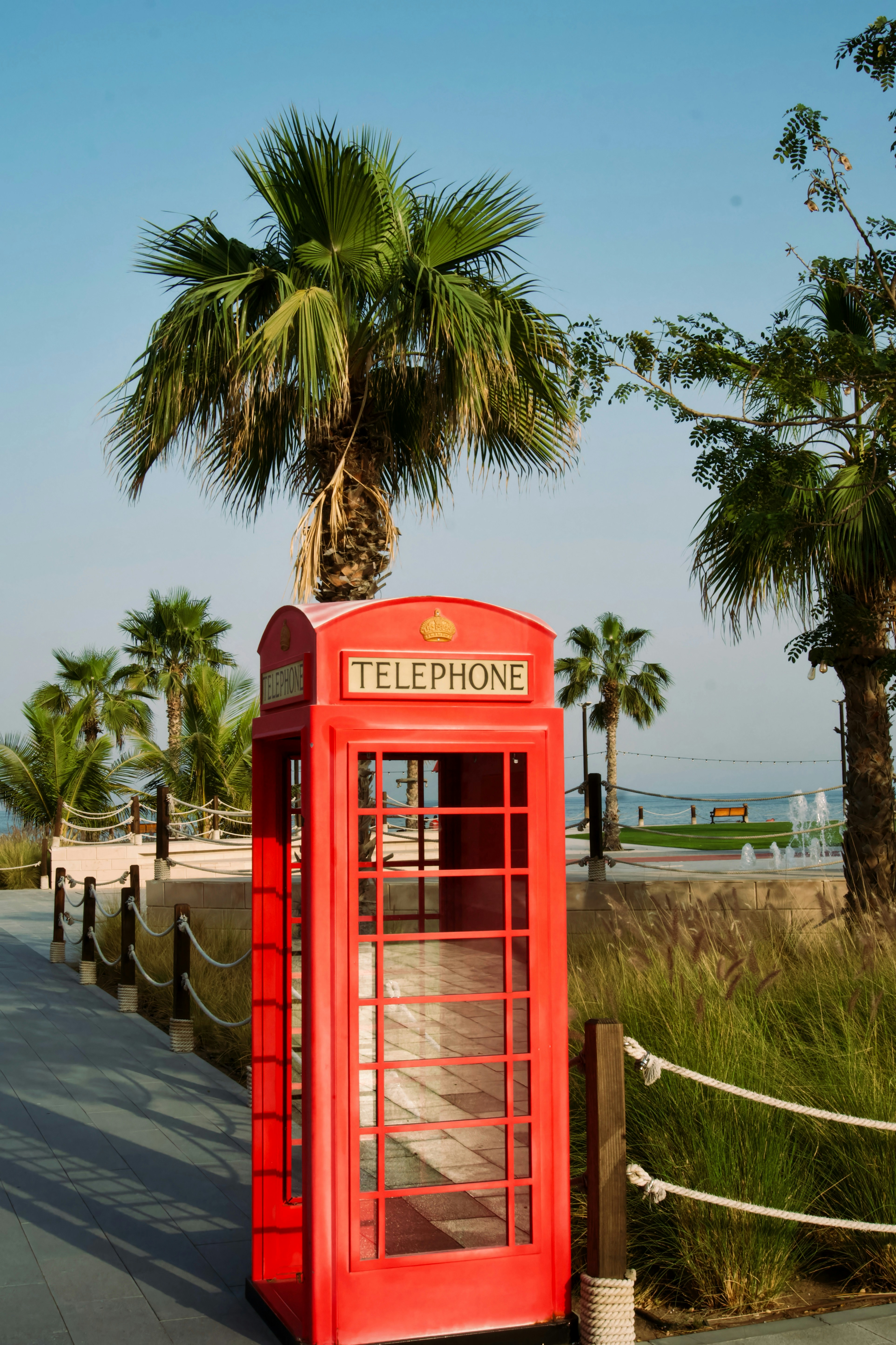 Bold Red Kiosk by the Sea: A Palm-Tree Corridor