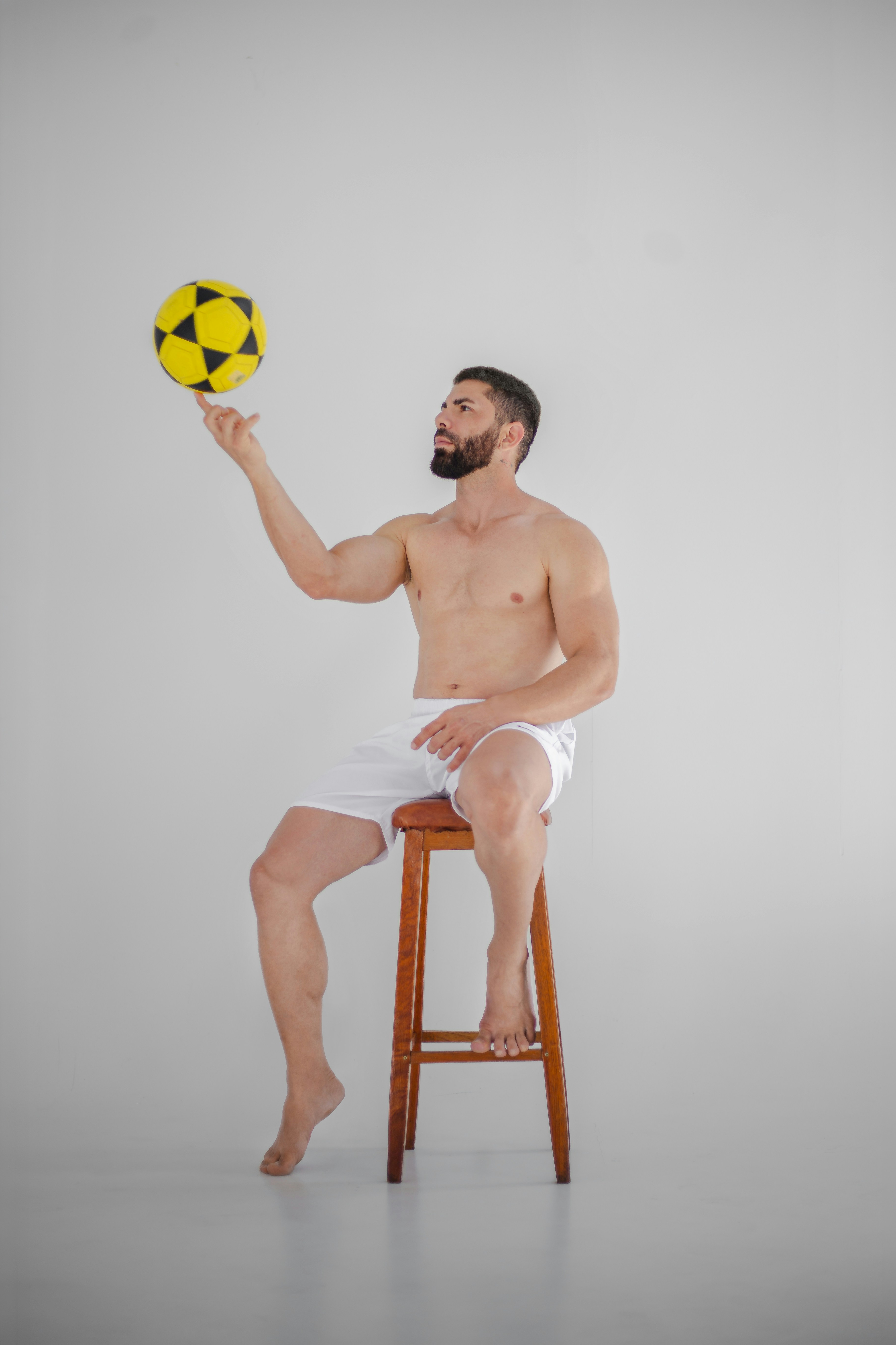 Seated Aeroball: A Shirtless Athlete in White Shorts Balances a Striped Ball
