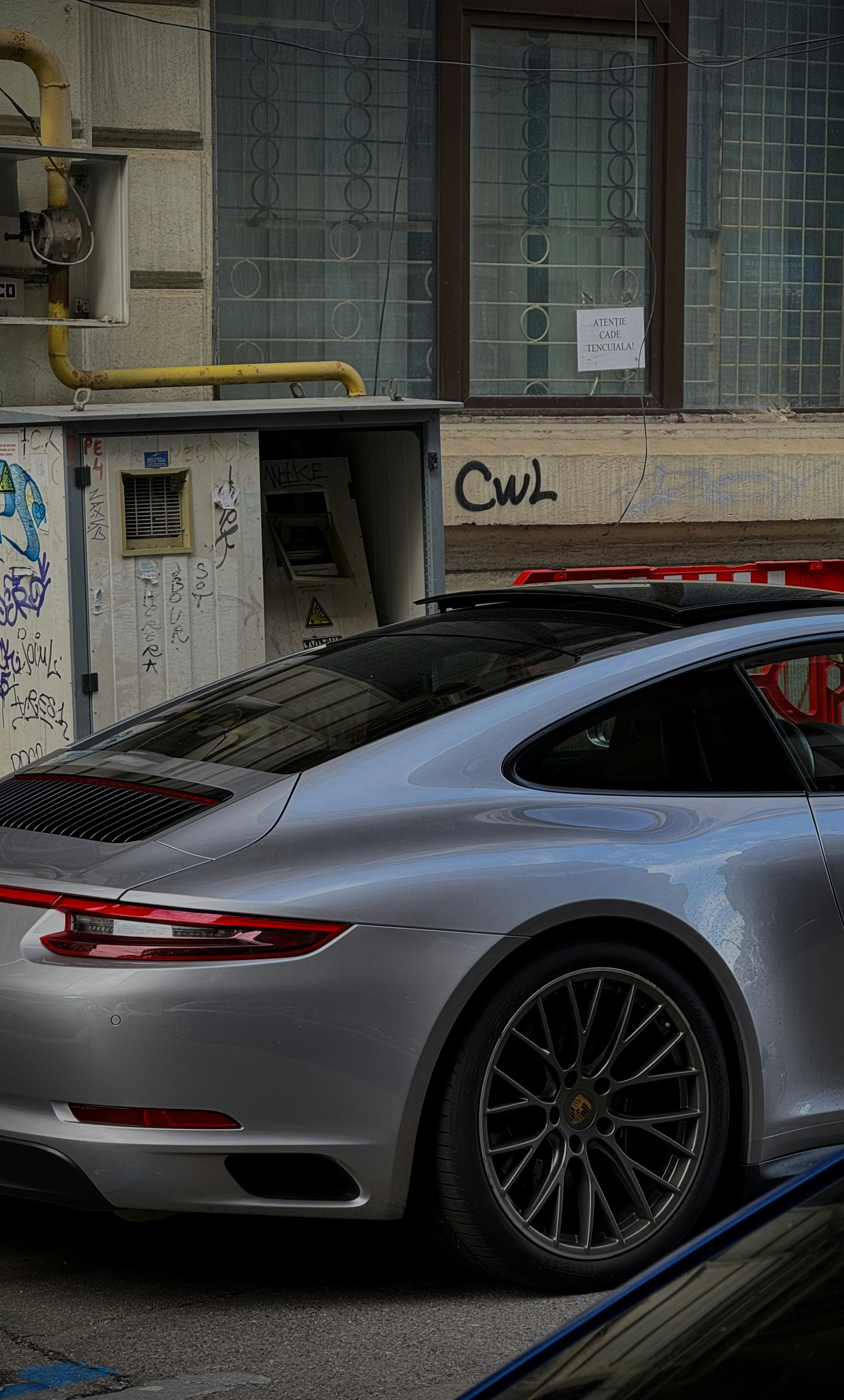 Chrome lines and streeted steel: a silver Porsche beside a graffiti-walled alley