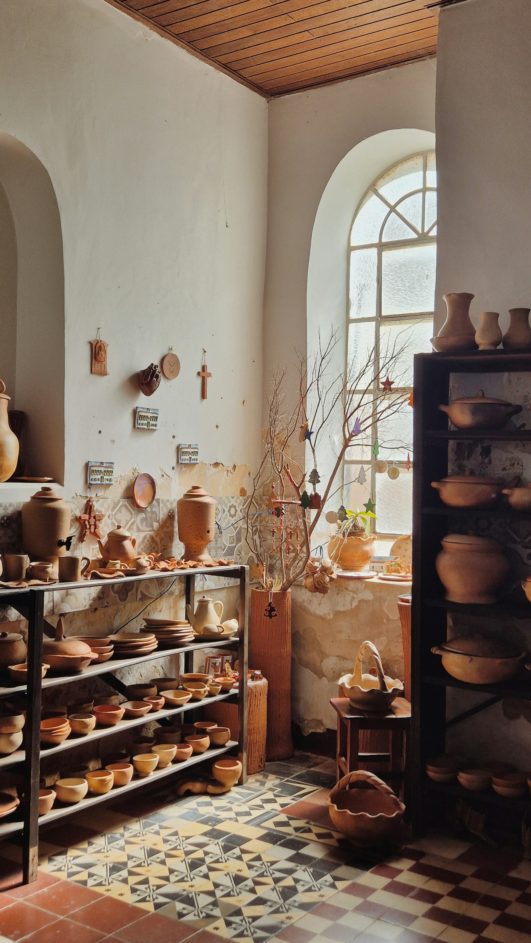 Rustic pottery atelier: sunlit shelves and arched window